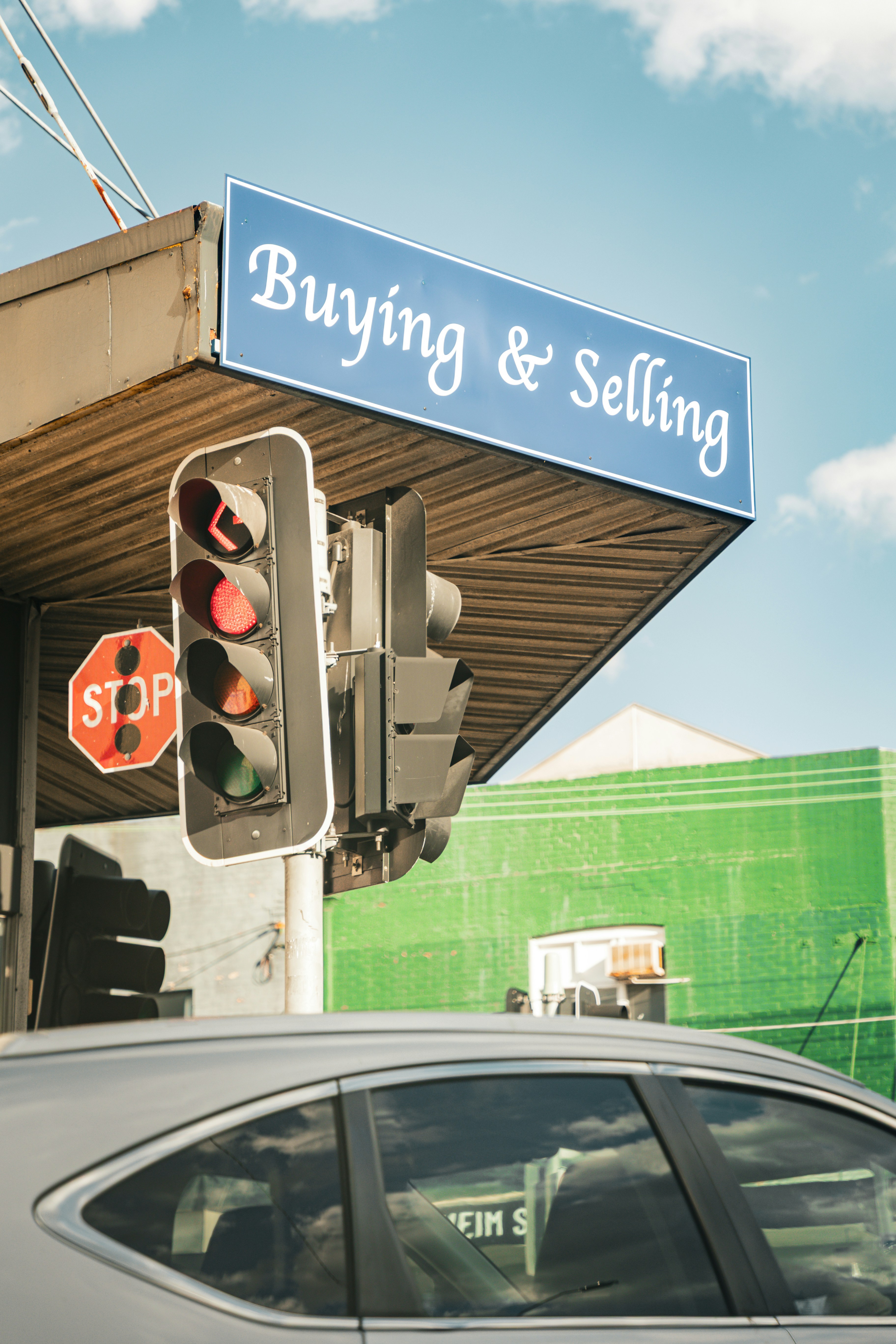 A "buying & selling" sign hangs above a traffic light. photo – Free Car ...