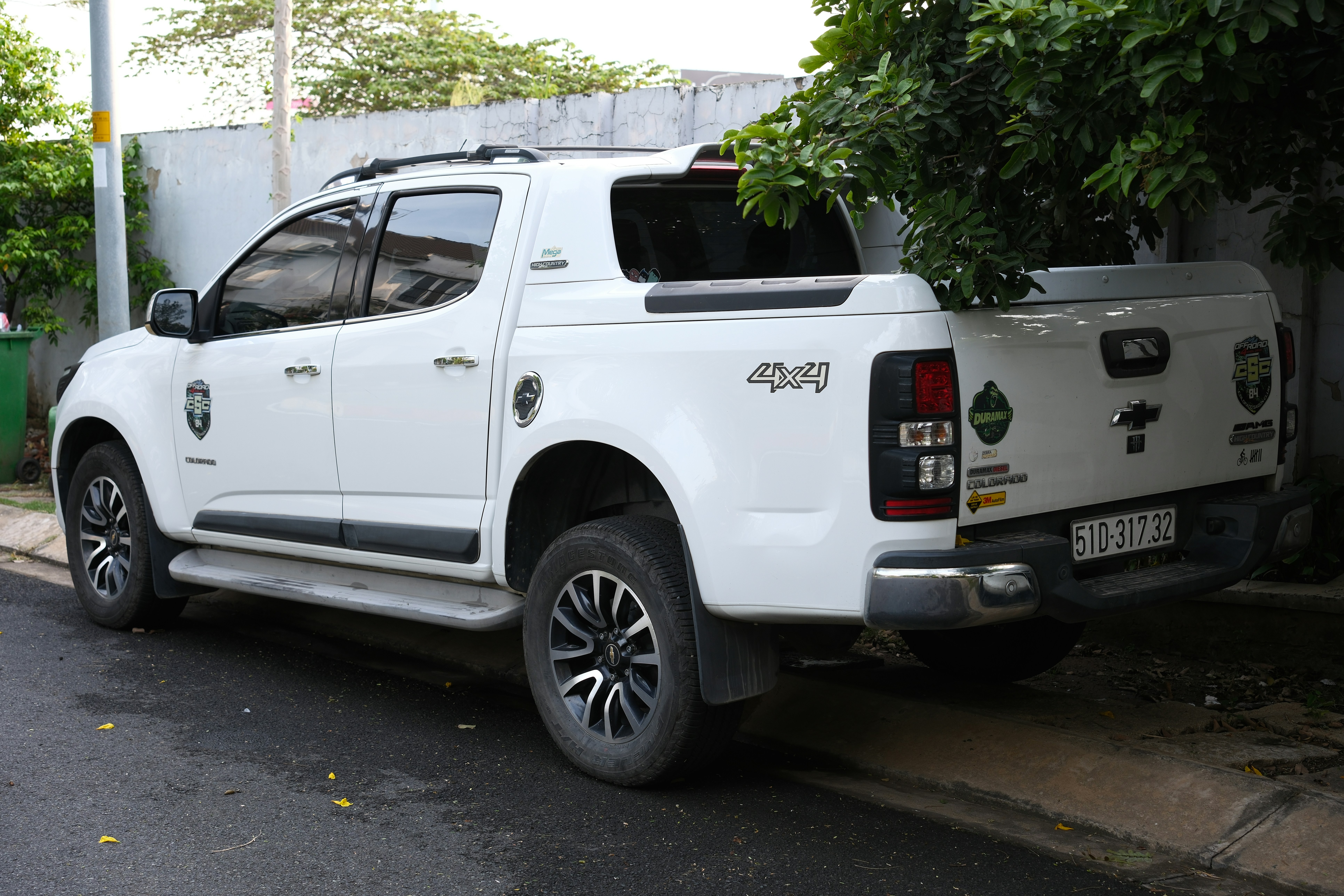 White 4x4 at Rest: Decal-Studded Crew Cab on a Quiet Urban Street