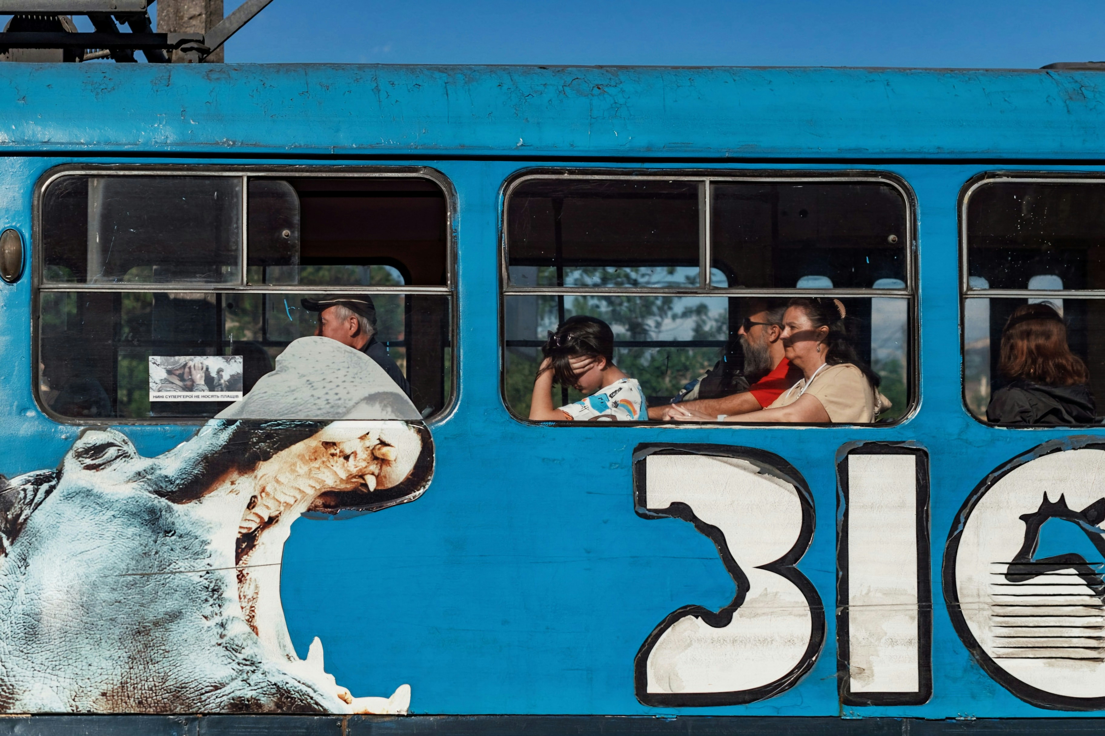 Blue Carriage, Bright Faces: Passengers Close to a Painted Shark's Gaping Mouth
