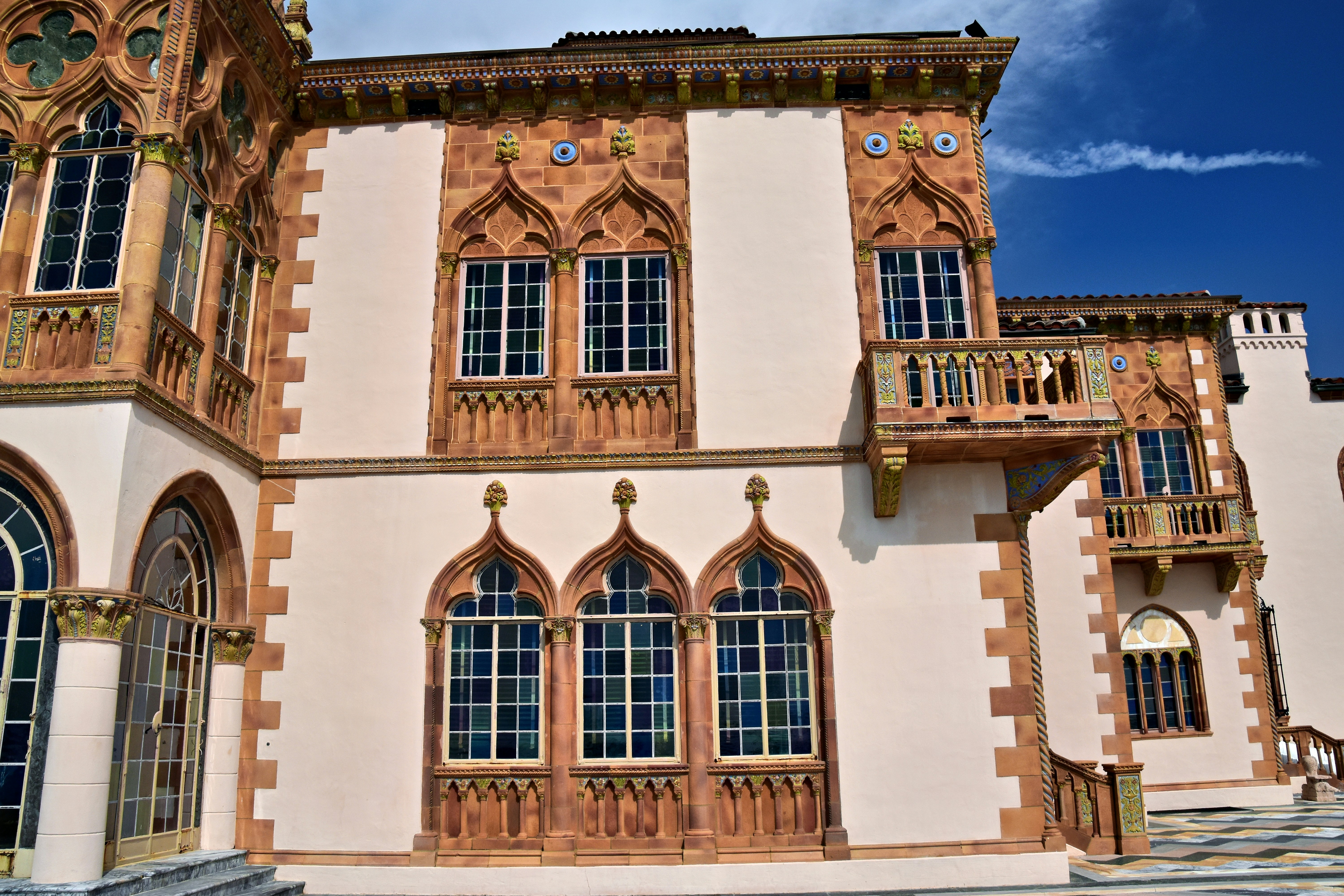 Terracotta Tracery in Sunlit Facade: Arched Windows and Ornate Stonework