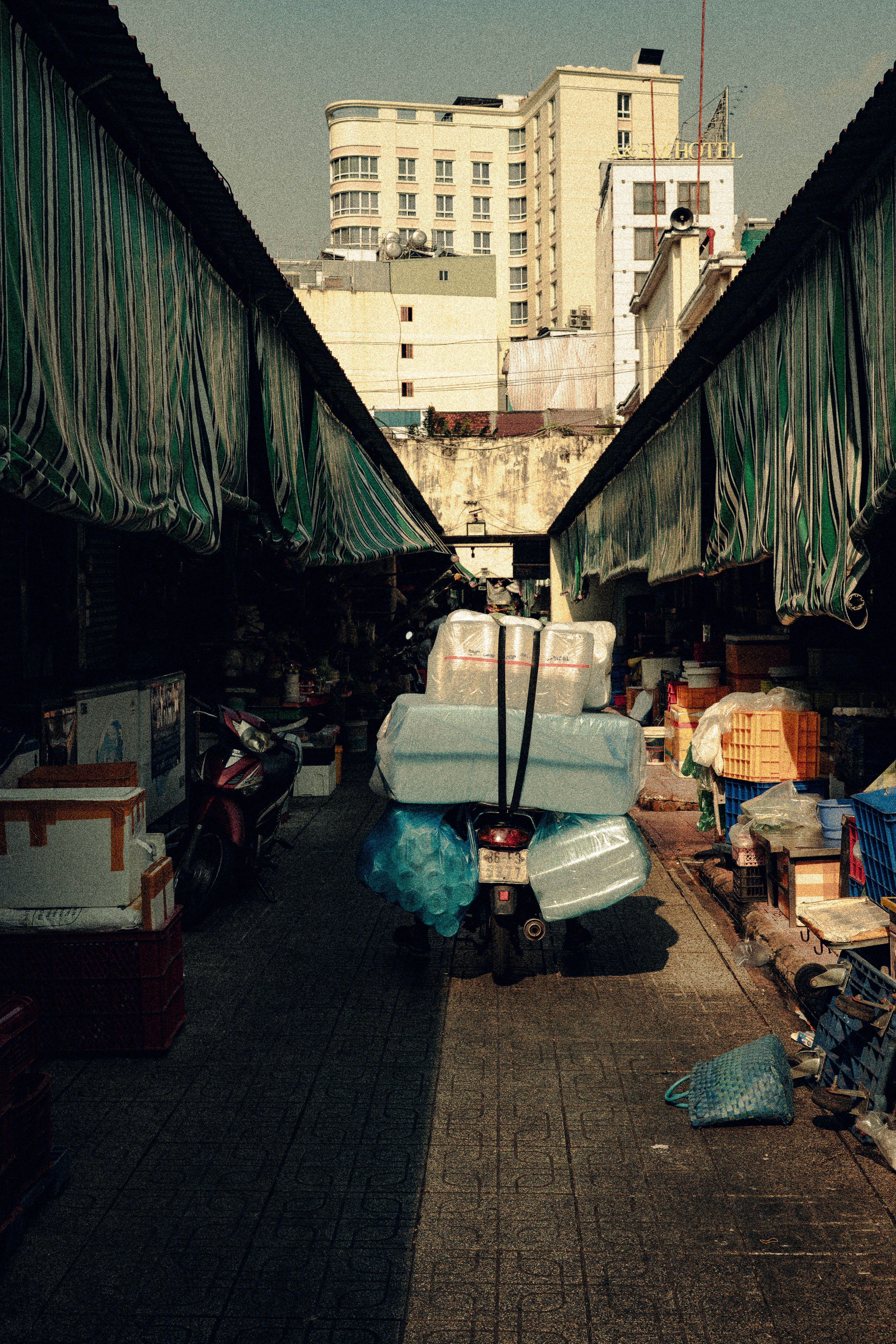 Foam Freight on a Narrow Market Lane Beneath Green Awnings