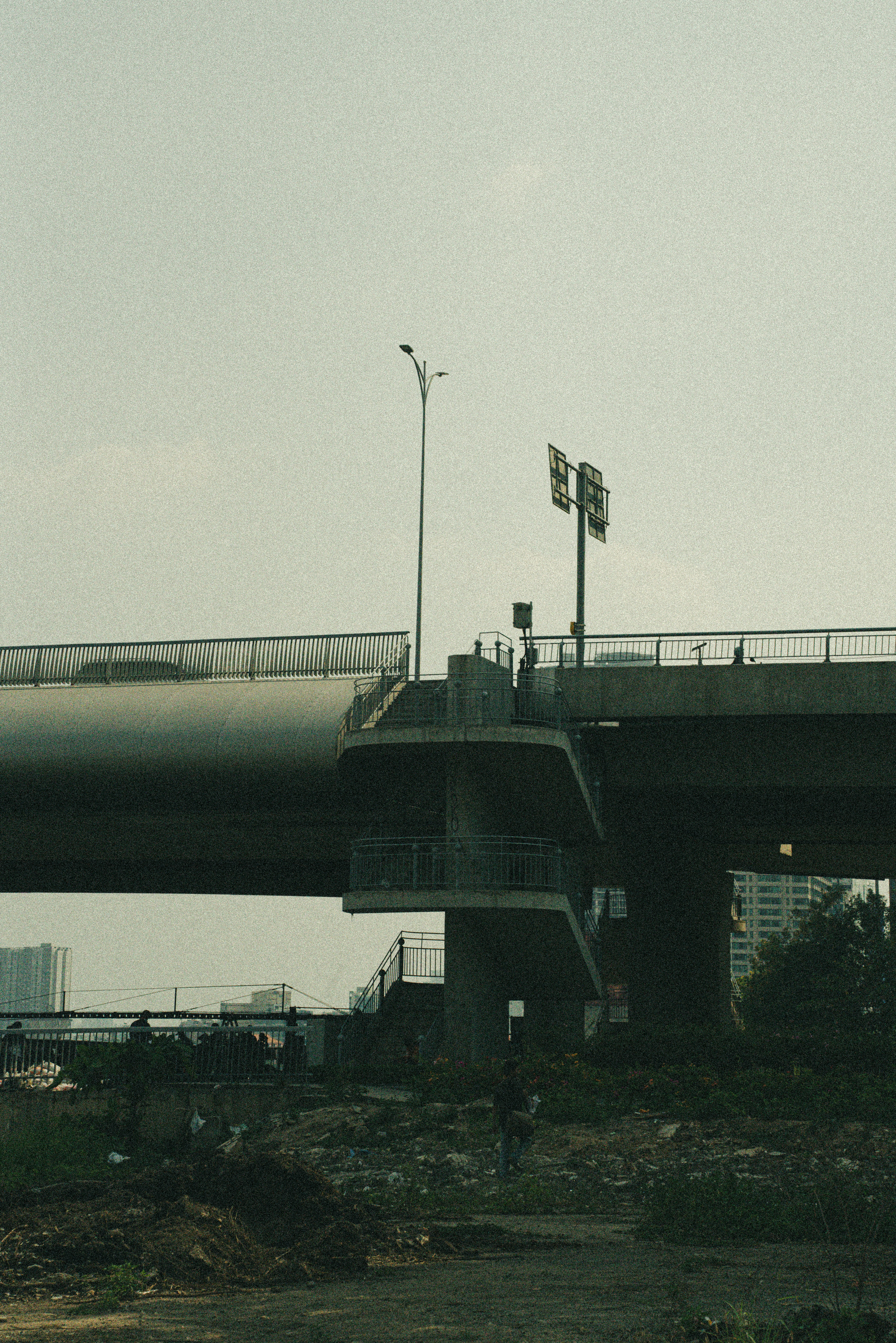 Under the Span: A lone figure amid rubble beneath a concrete overpass