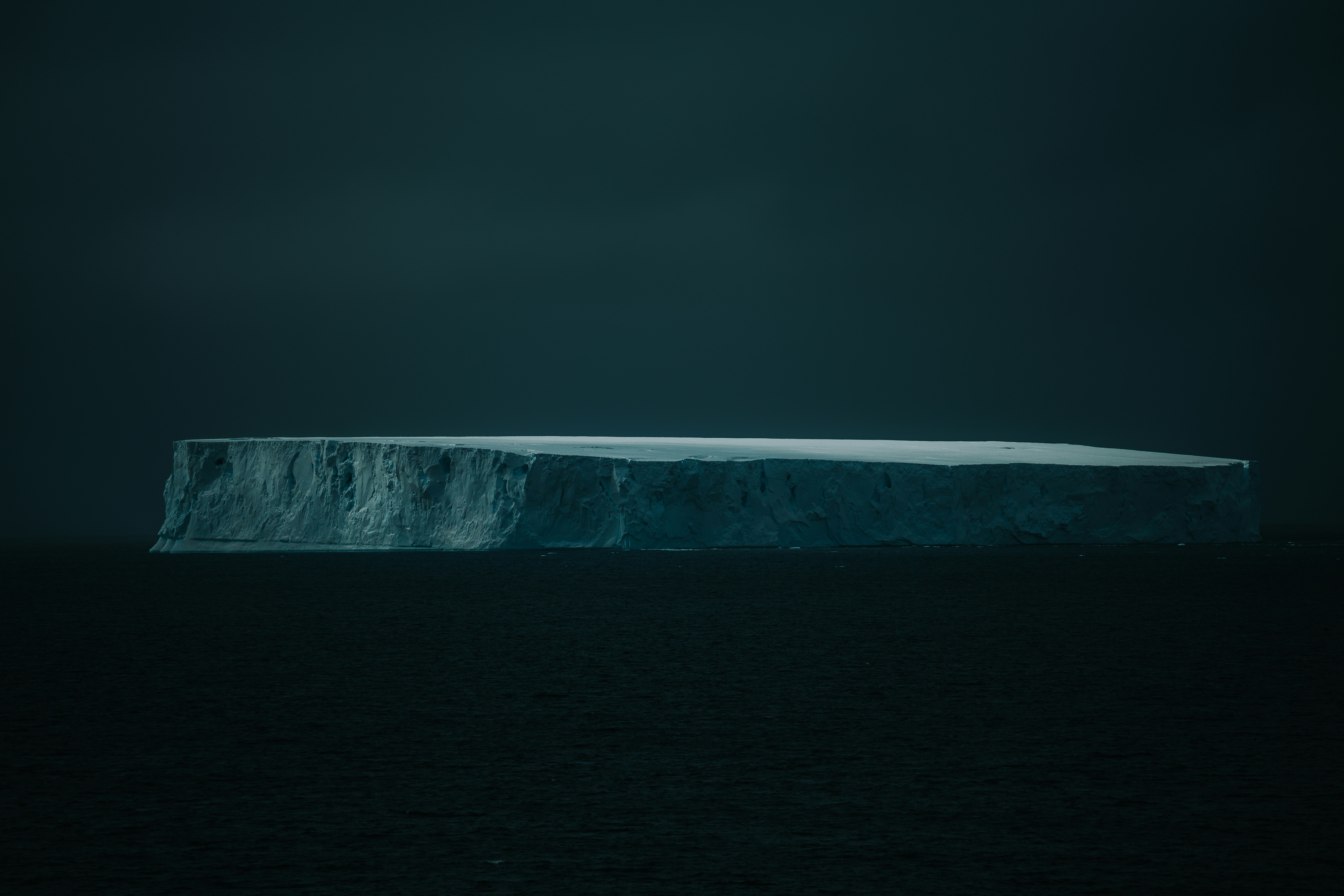 A huge, flat iceberg floats on dark water. photo – Free Travel Image on ...