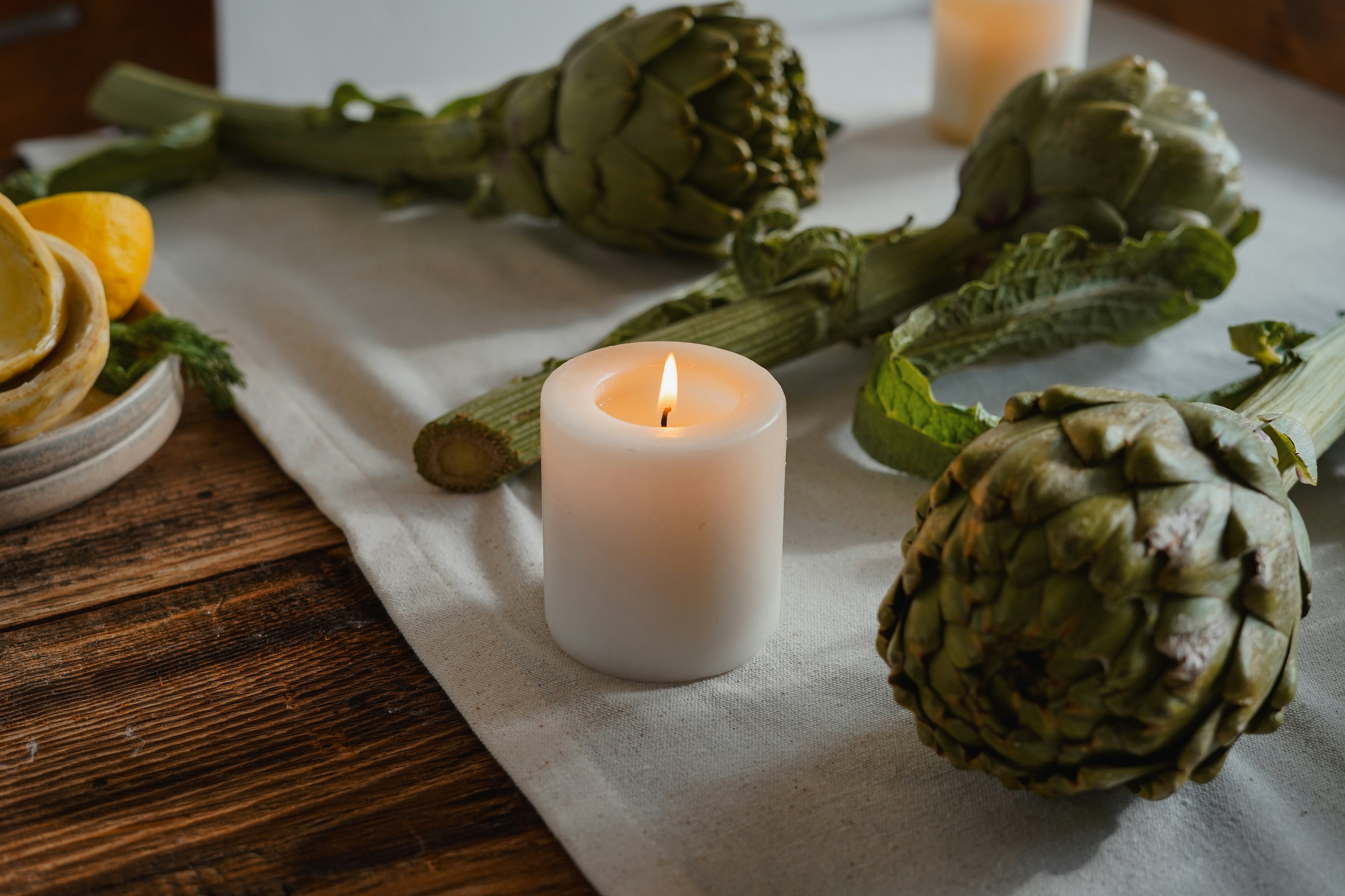 Candlelit Calm: Artichokes and Artful Light on a Wooden Table