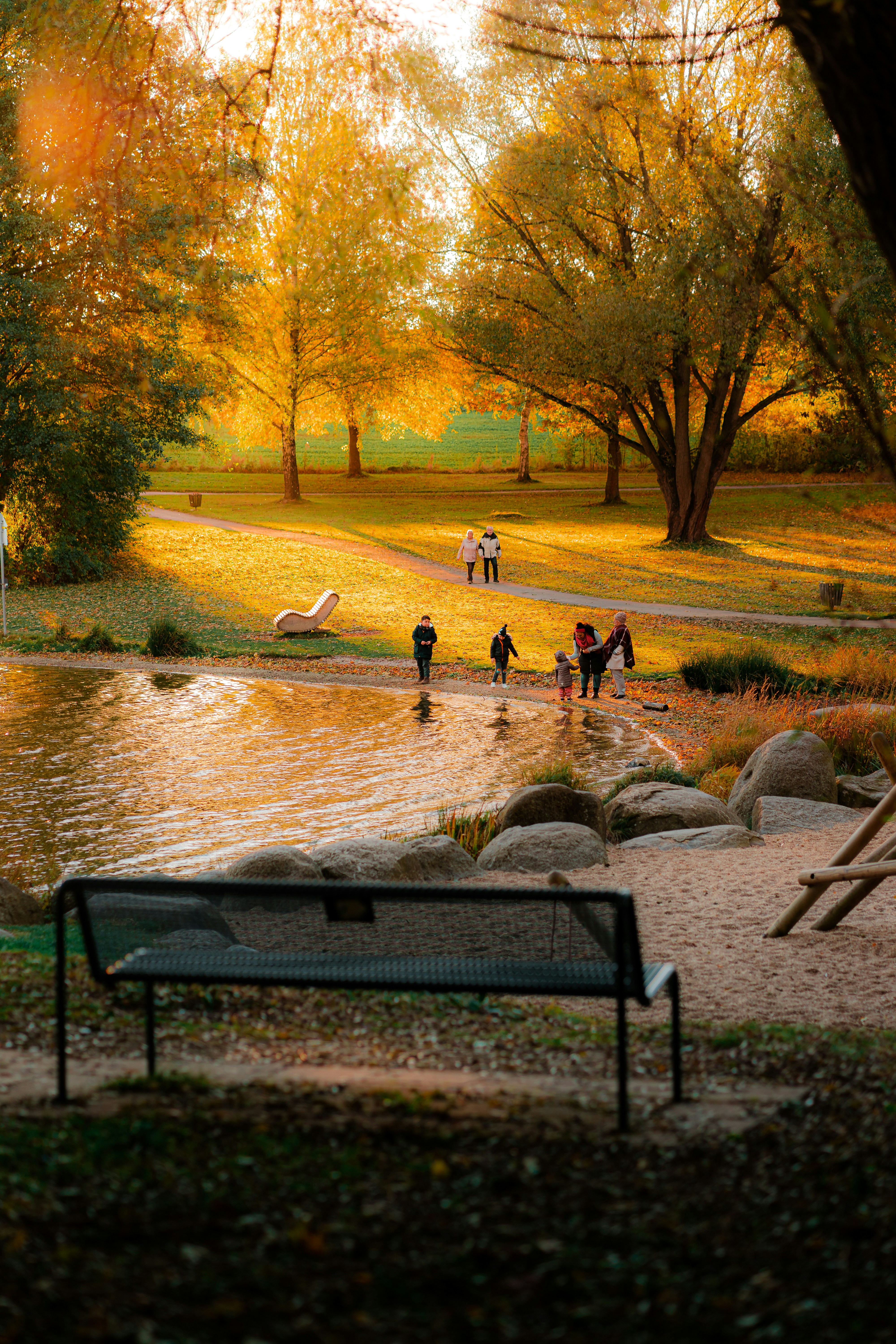 Golden-Hour Stroll by the Reflective Pond Under Amber Canopy