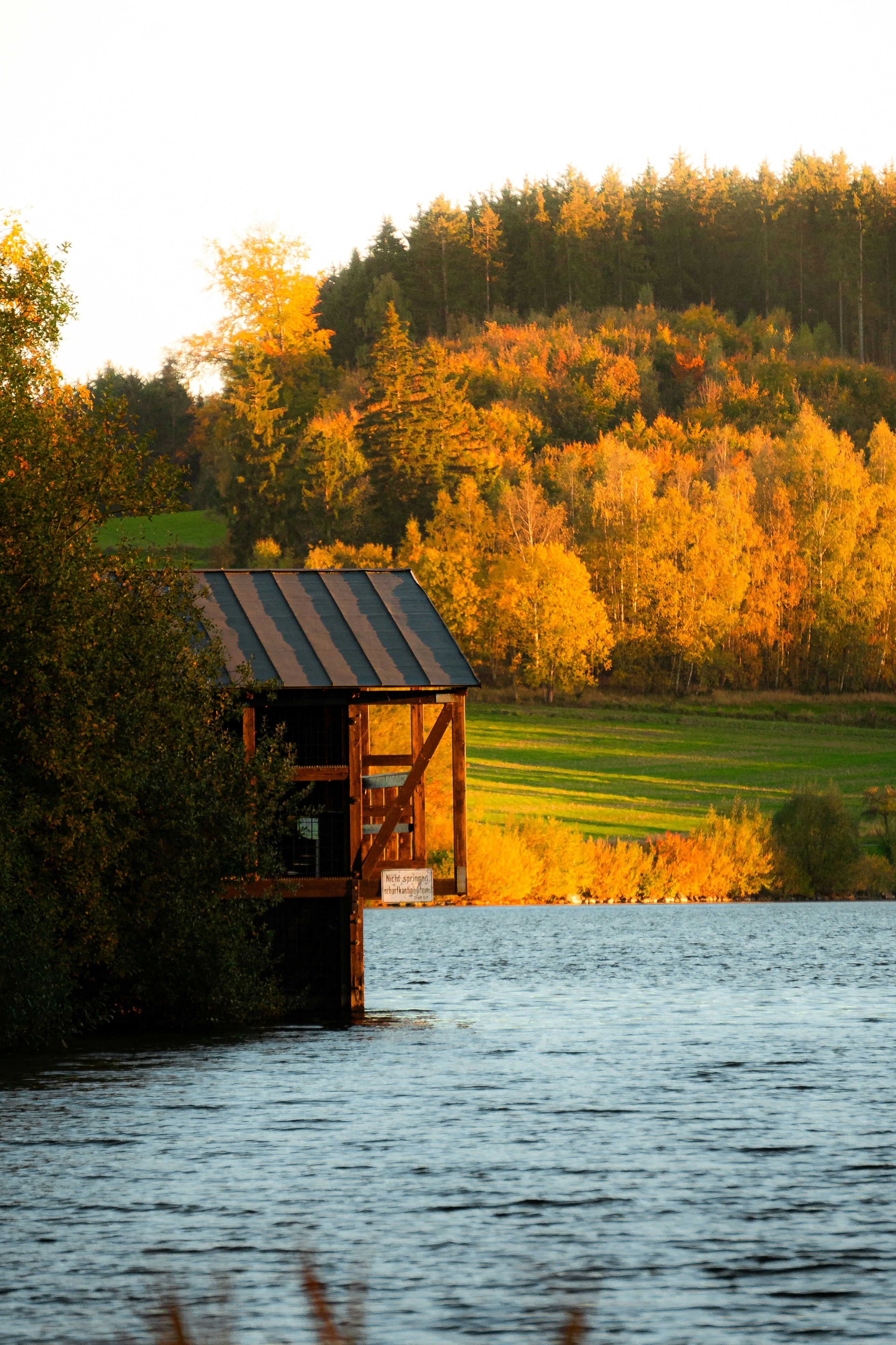 Autumn Light Drapes a Waterfront Boathouse by a Quiet Lake