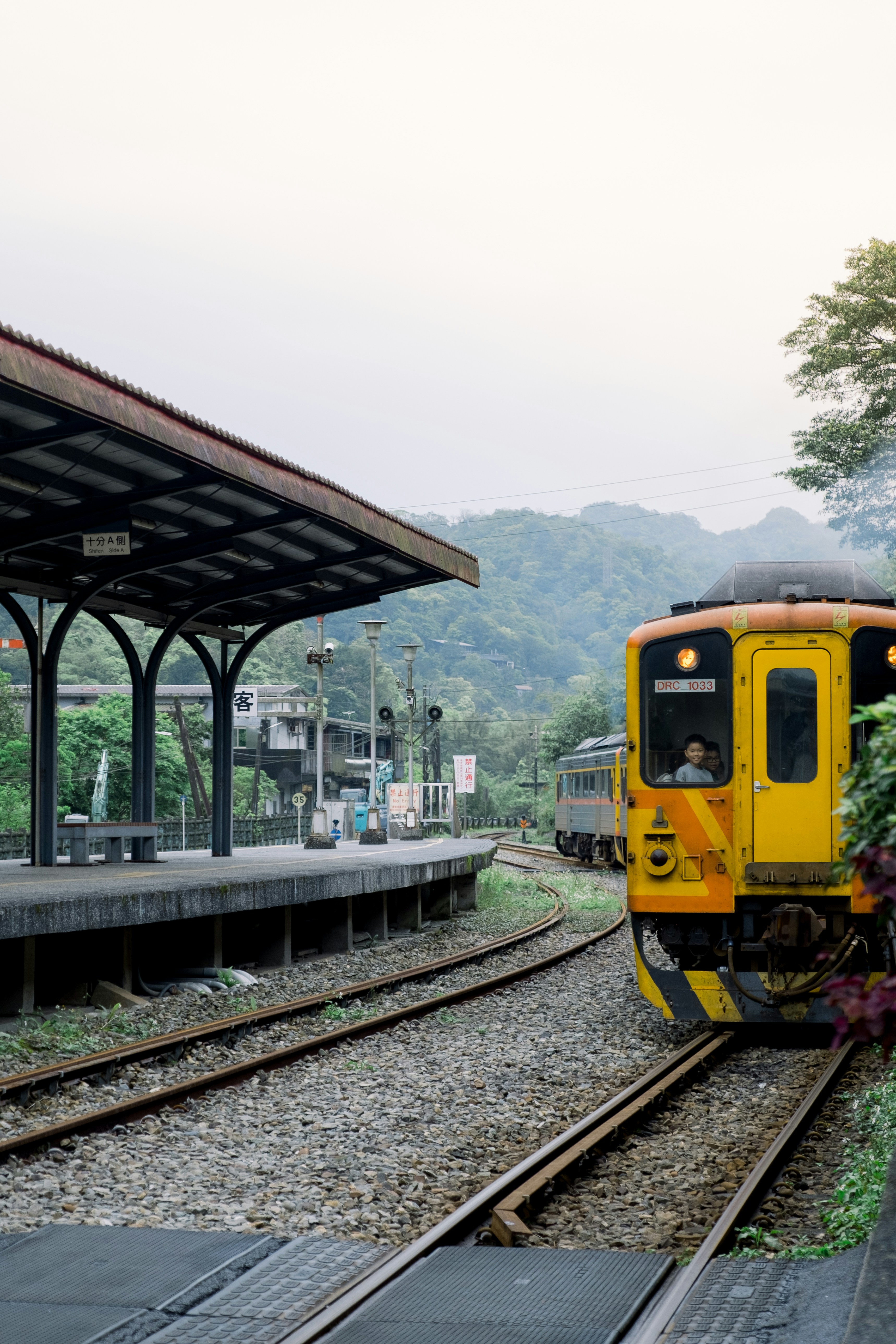 A yellow train arrives at a quiet train station. photo – Free Human ...