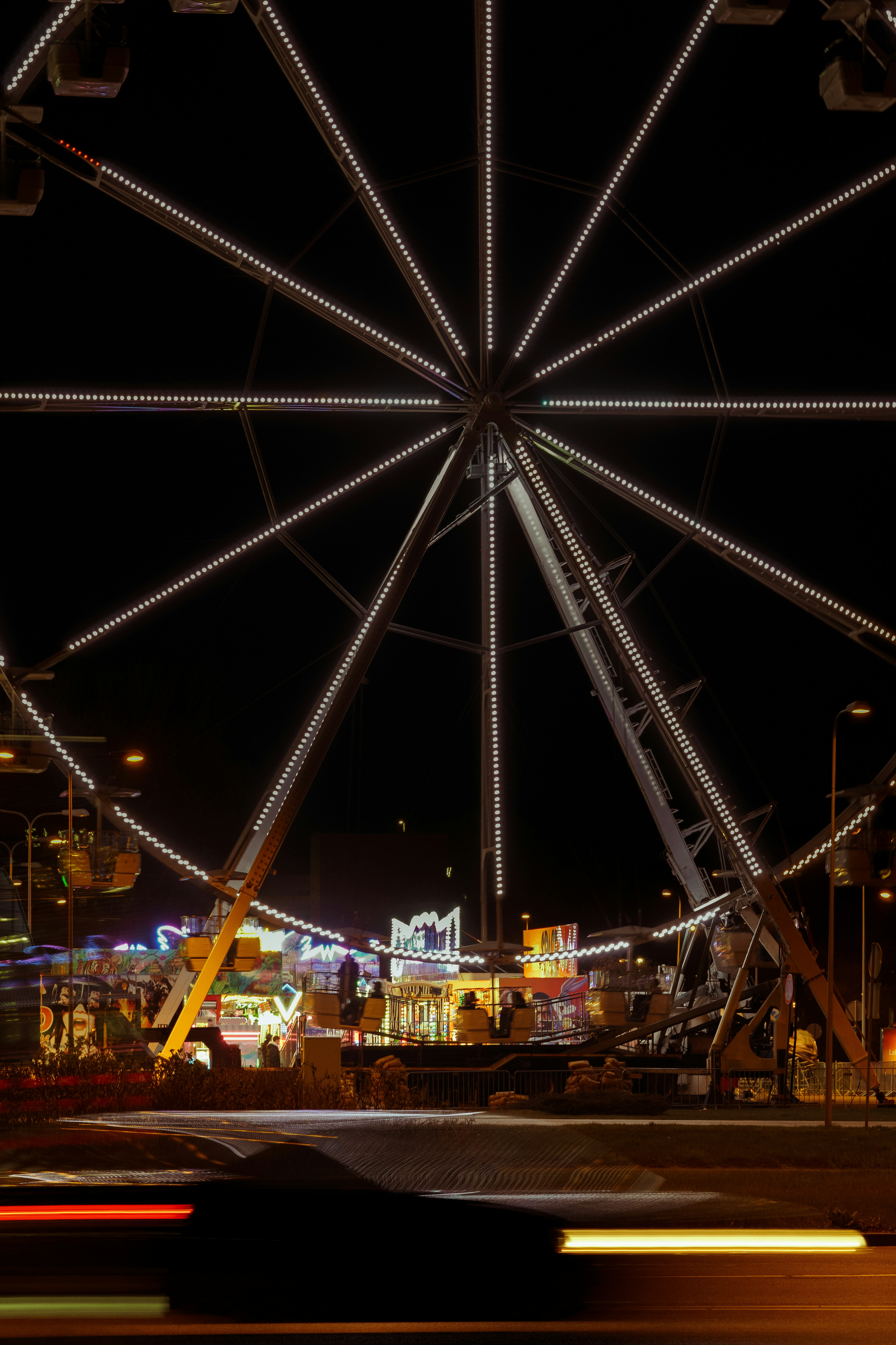 Neon Spokes: Night Ferris Wheel Illuminates a Busy Fairground