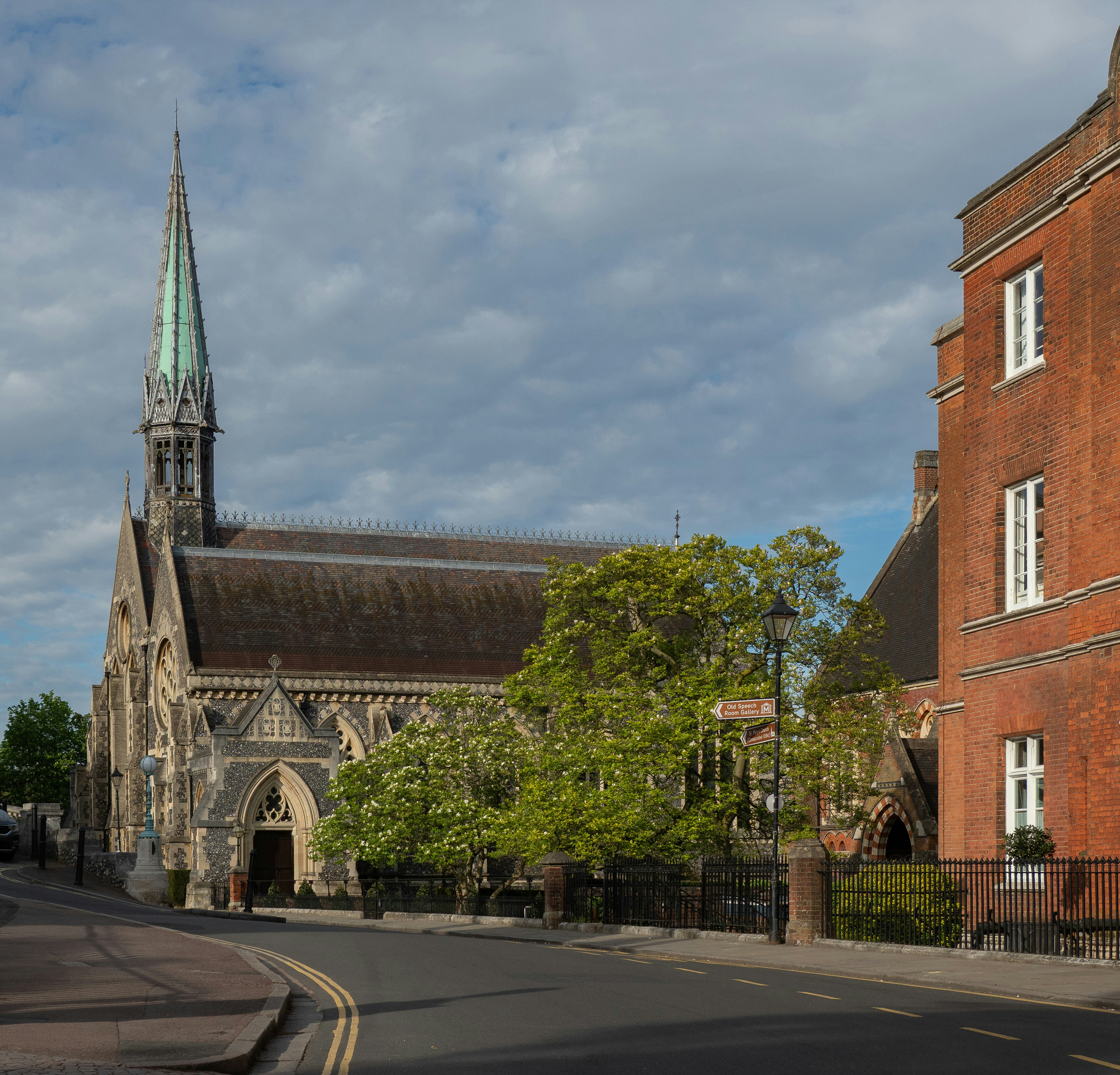 Victorian-era church juxtaposed with modern architecture, framed by blossoming trees and a cloudy sky.