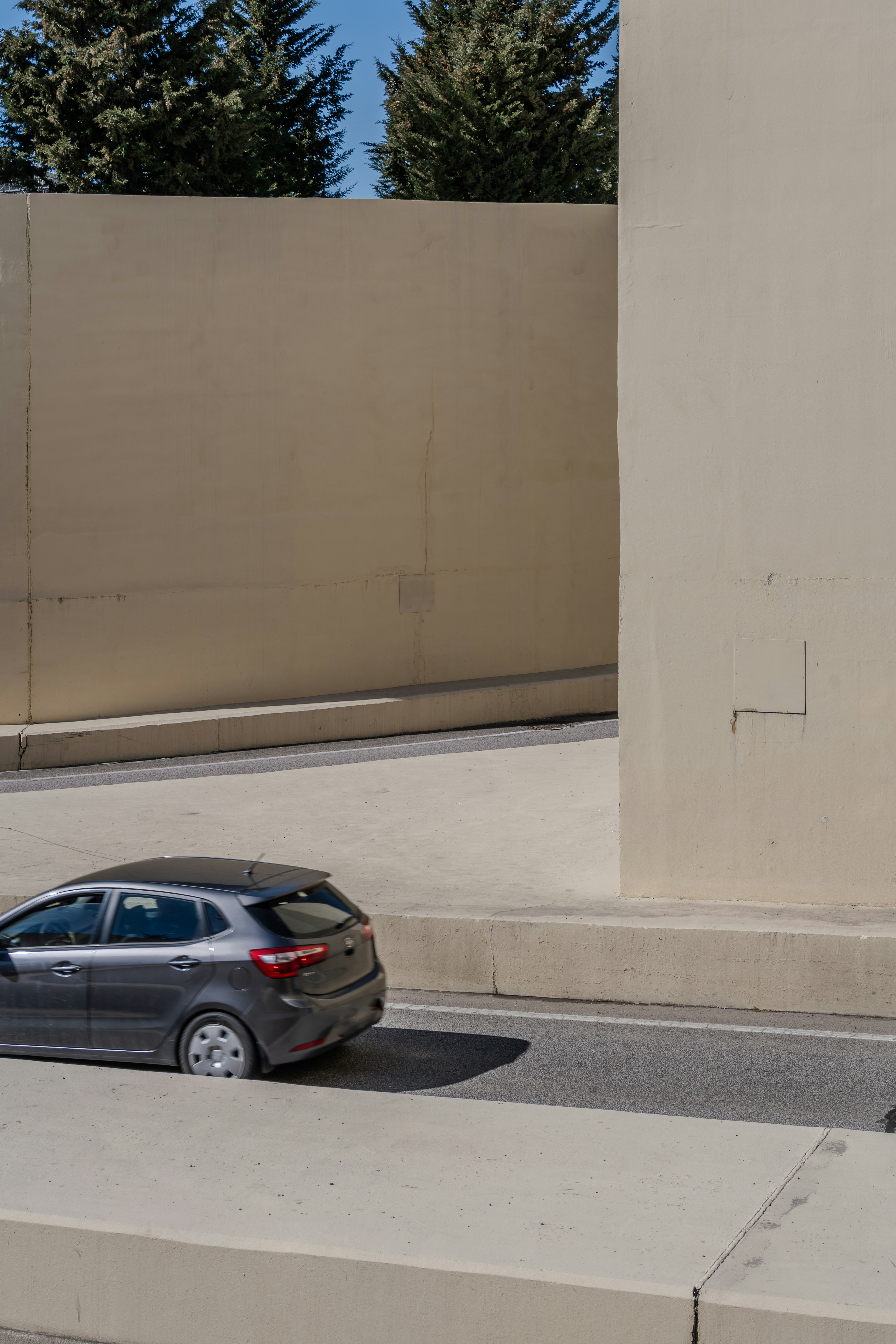 A car drives on a road next to a wall. photo – Free Car Image on Unsplash