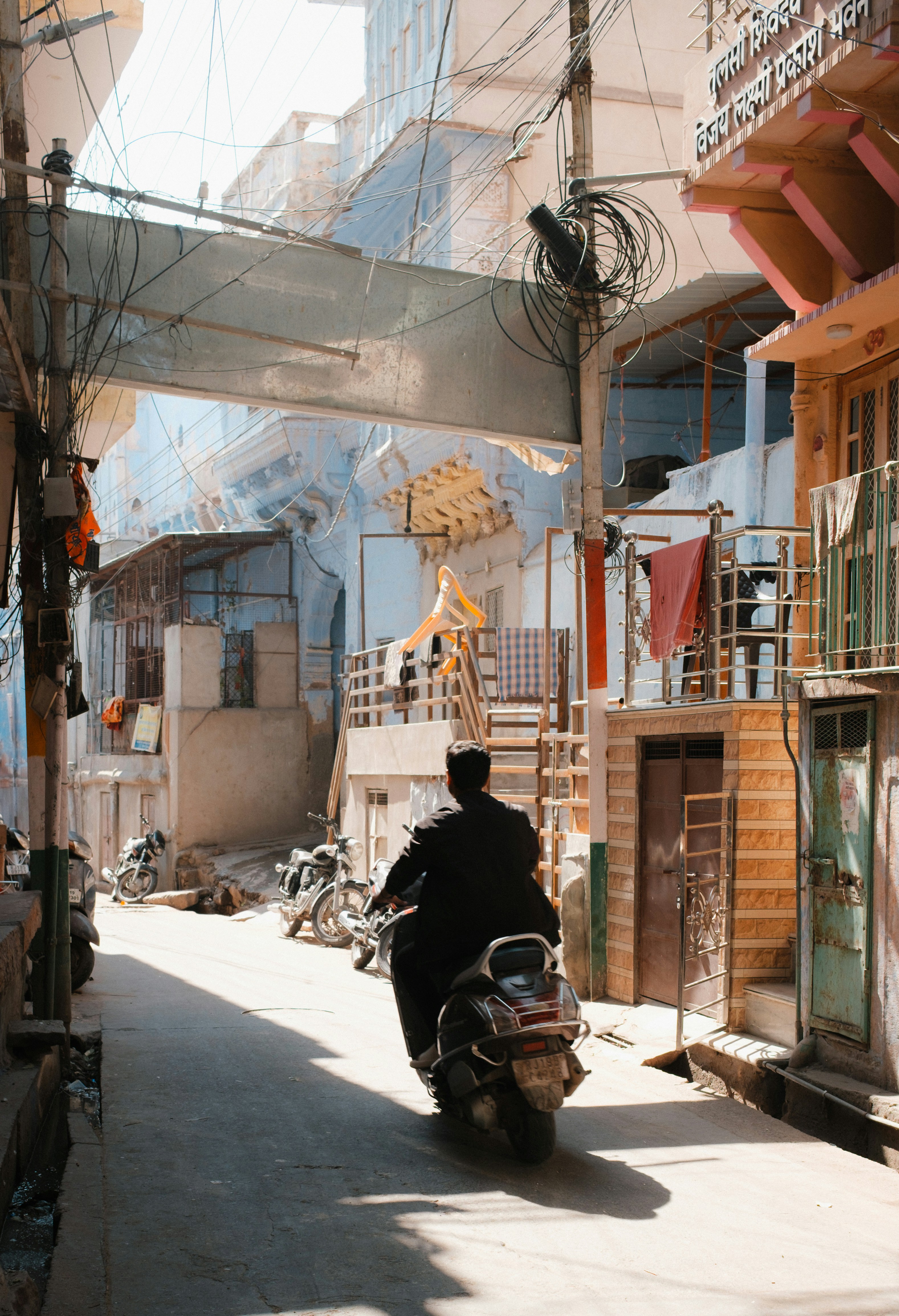 A person rides a scooter down a narrow street. photo – Free People ...