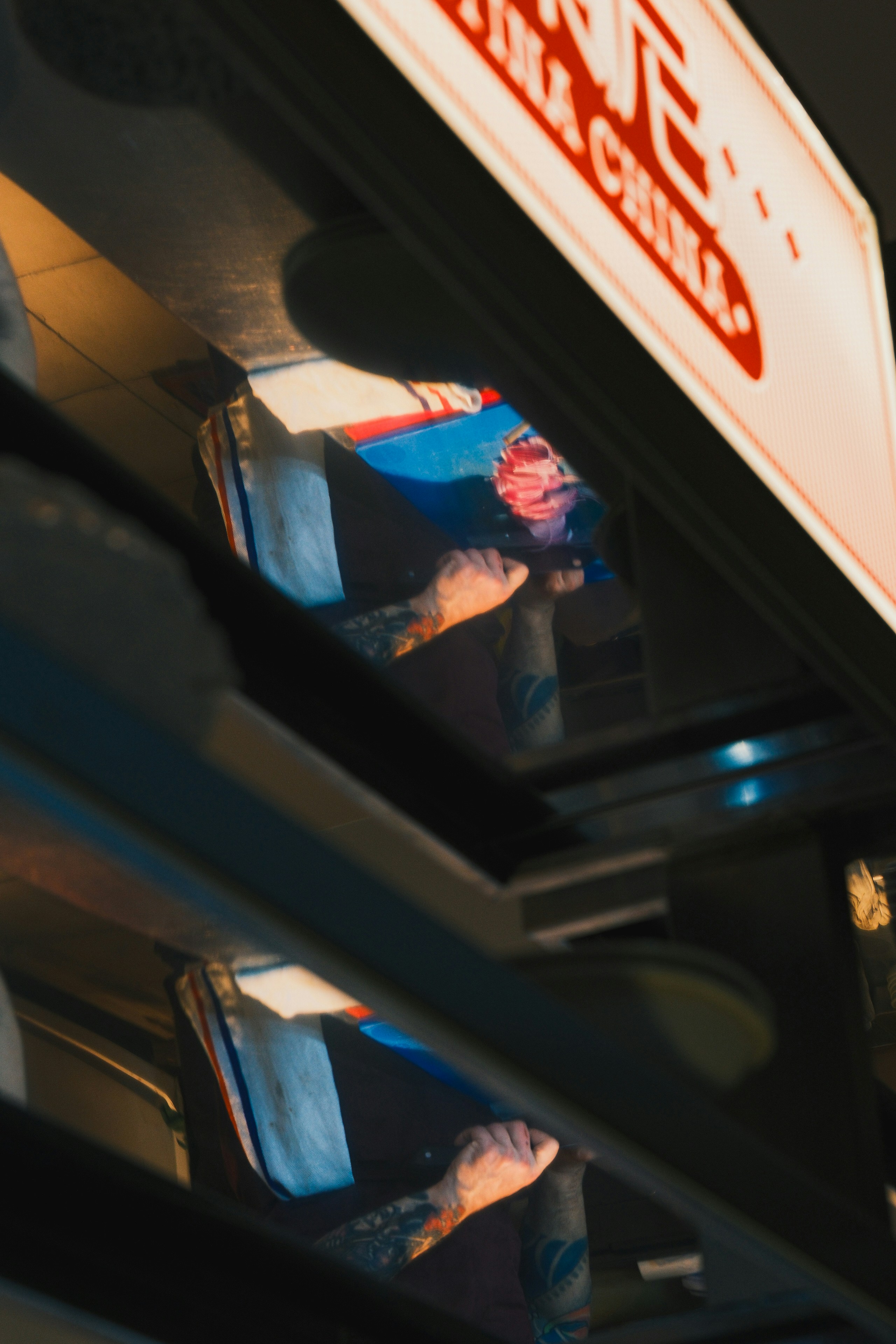 Una persona se refleja en un vidrio, cerca de un letrero de una tienda ...