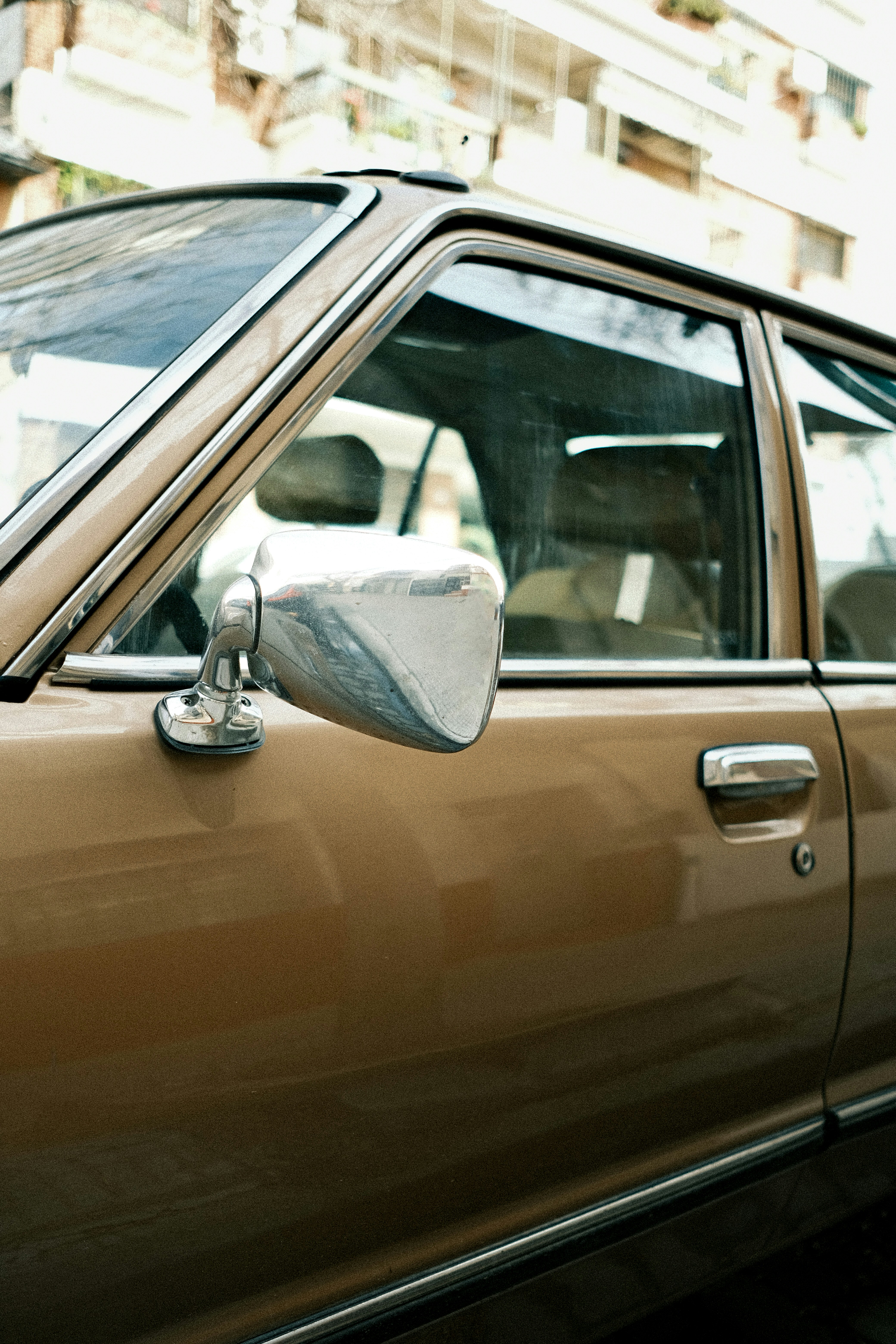 Beige Classic Car Mirror: Quiet Reflection on a Street-Side Door