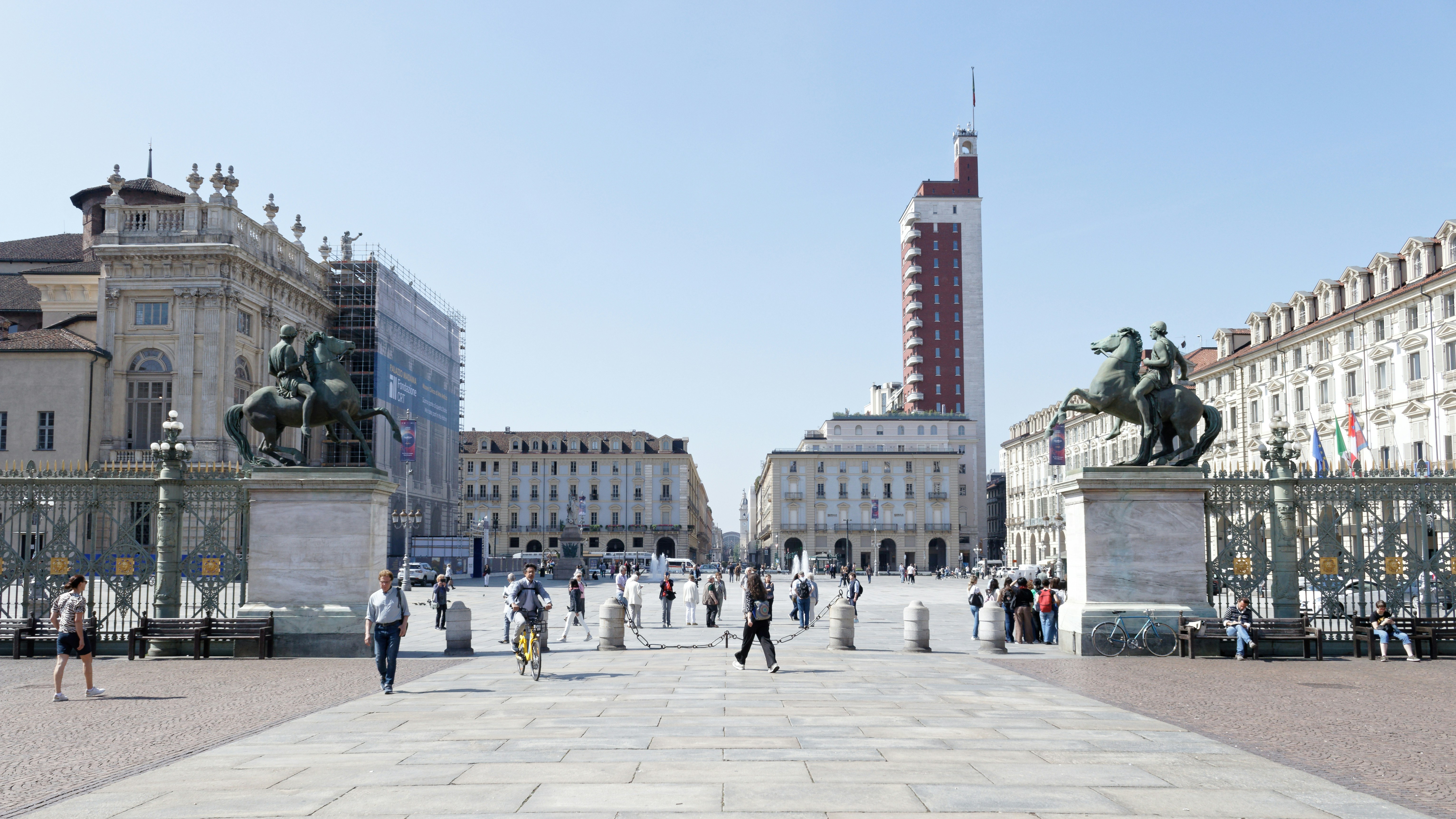 Aurea Piazza: stately gates and equestrian guardians at the sunlit esplanade