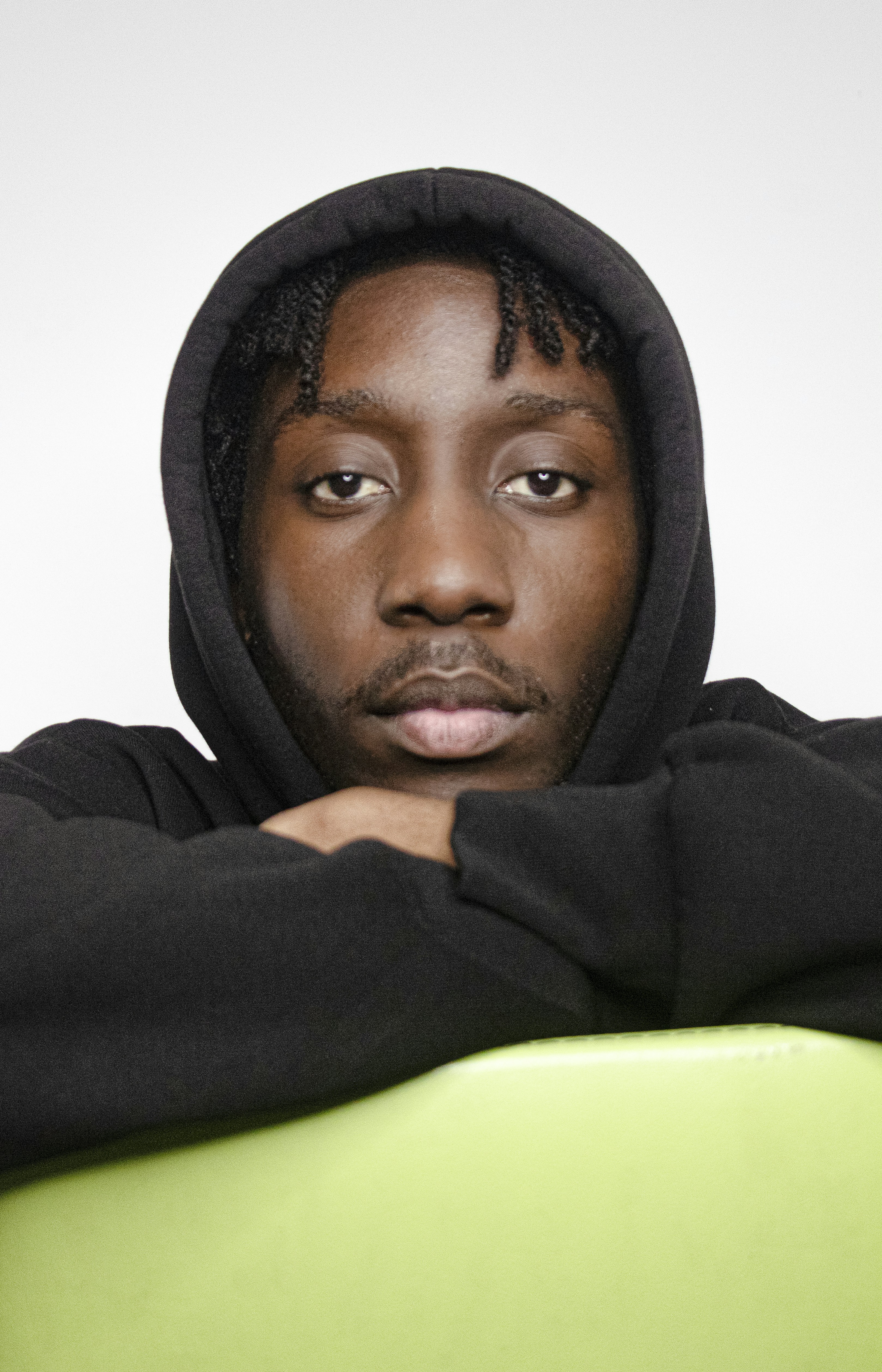 Direct Gaze in a Minimal Portrait: Hooded Calm Against Lime