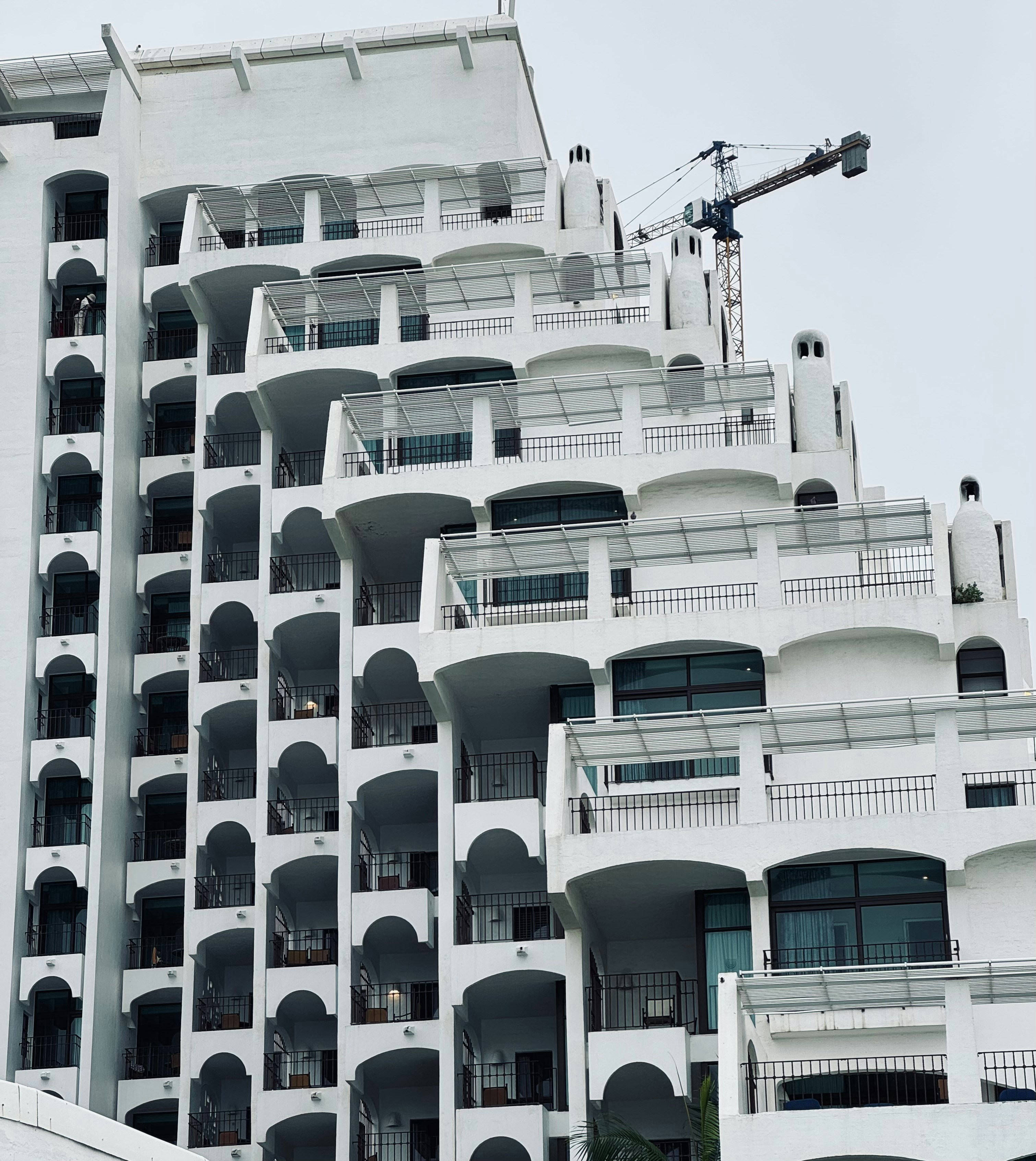 Archway Chorus: A White Facade Rehearsing Geometry Under a Construction Crane