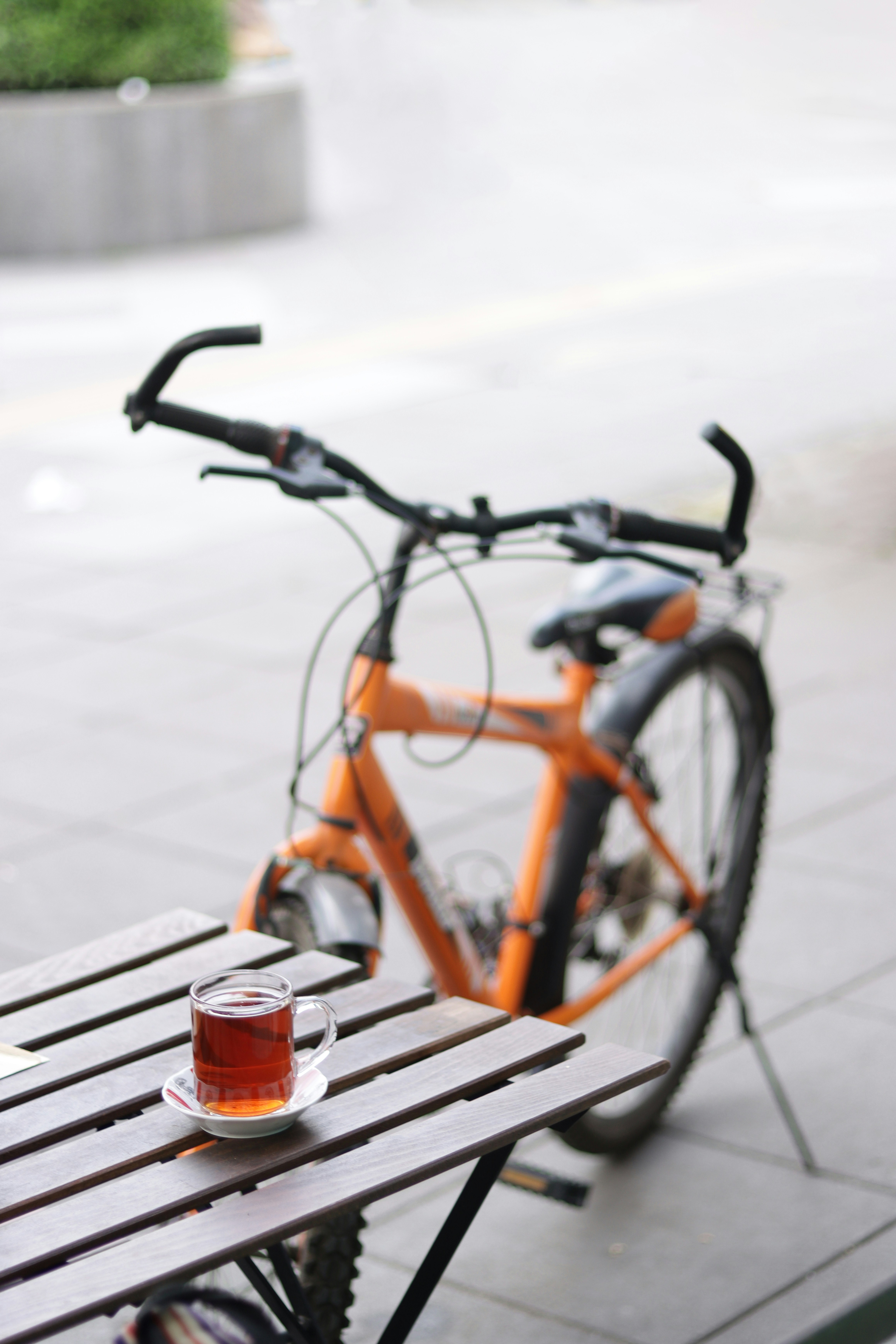 Amber Tea on a Wooden Table as an Orange Bicycle Recedes into Soft Focus