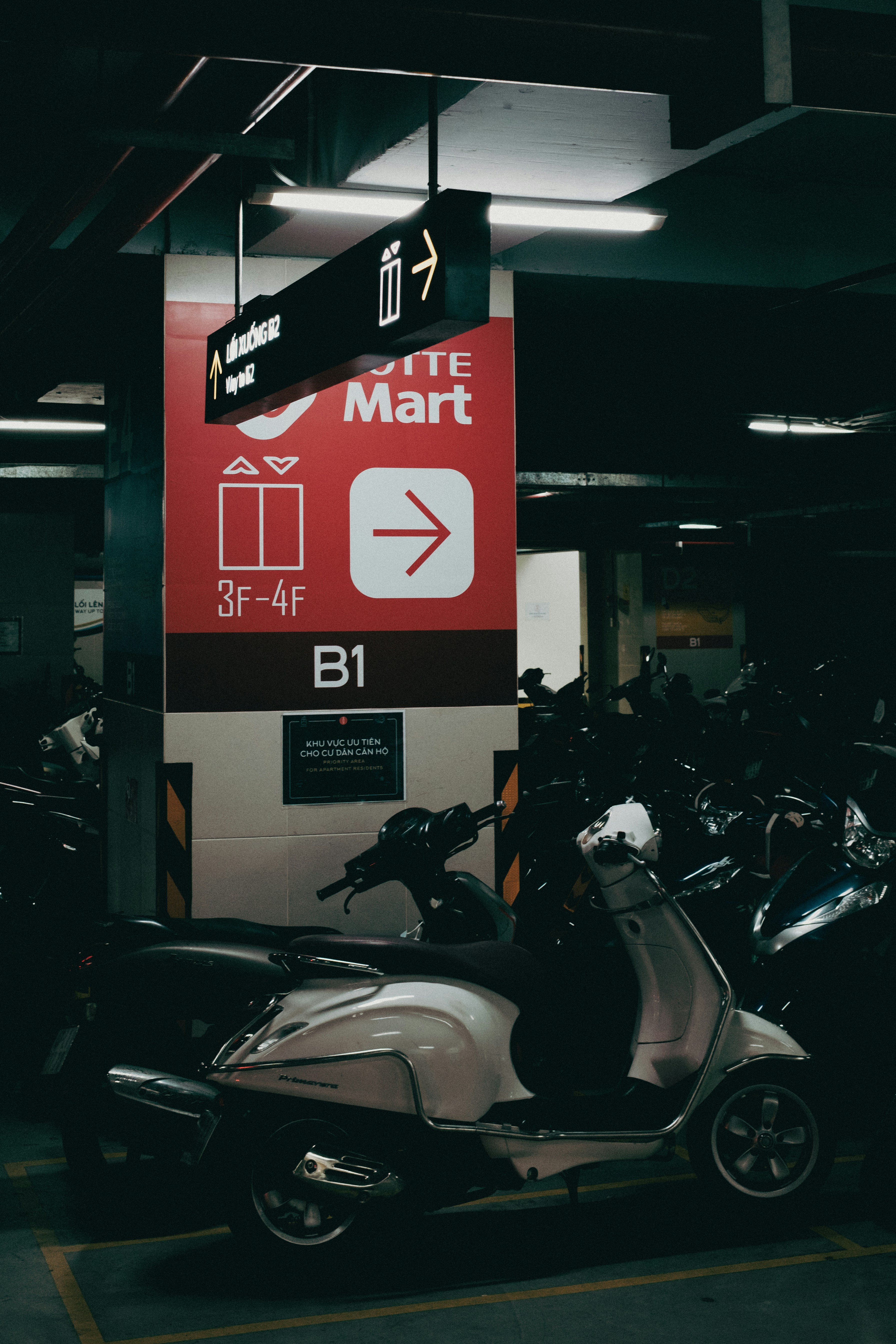 Red Pillar Signpost: Directional Arrows in a Dim Parking Garage