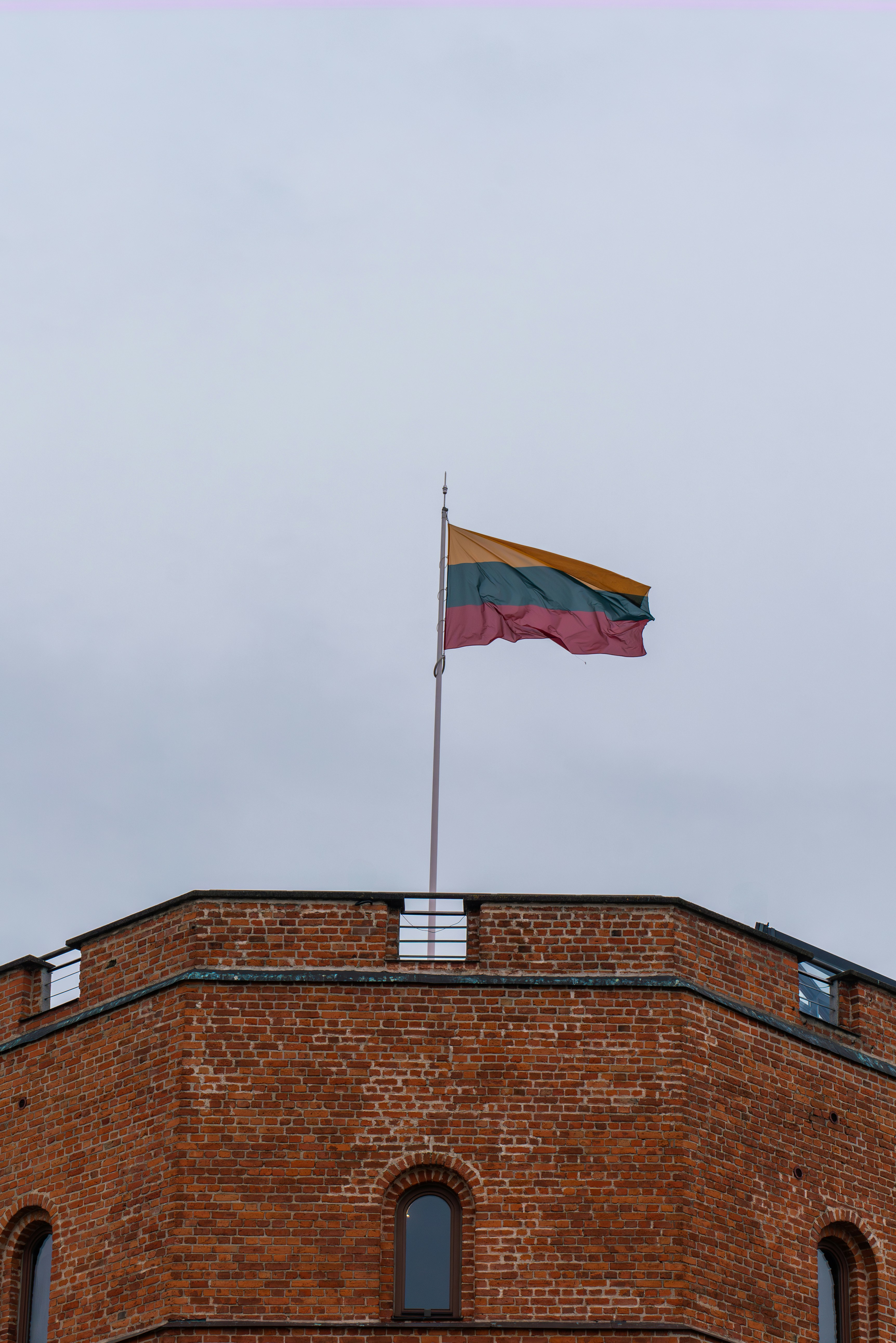 Historic Fortress | The lithuanian flag flies atop a brick tower.