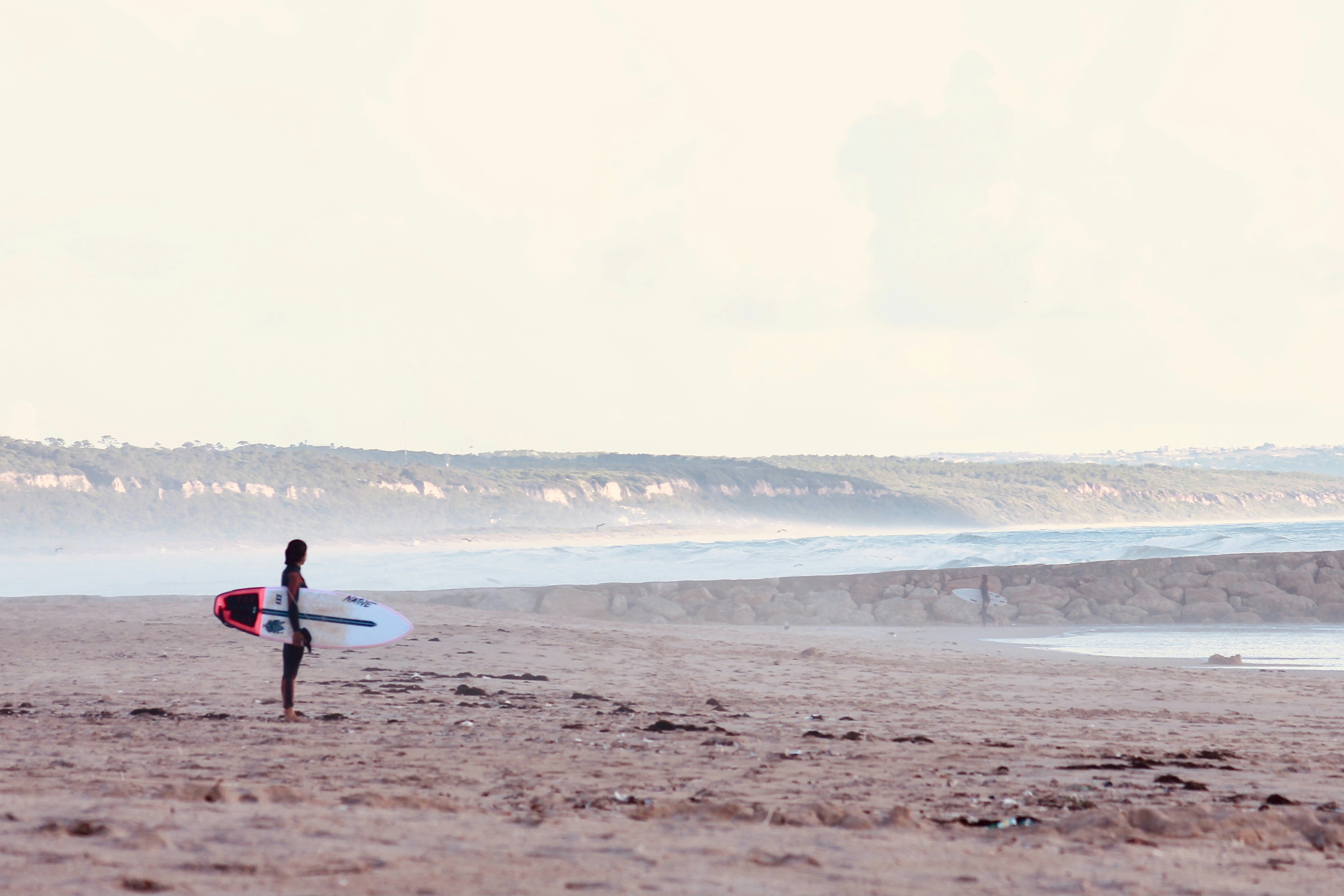 Lone Surfer at the Quiet Shore Under Dawn's Soft Pastels