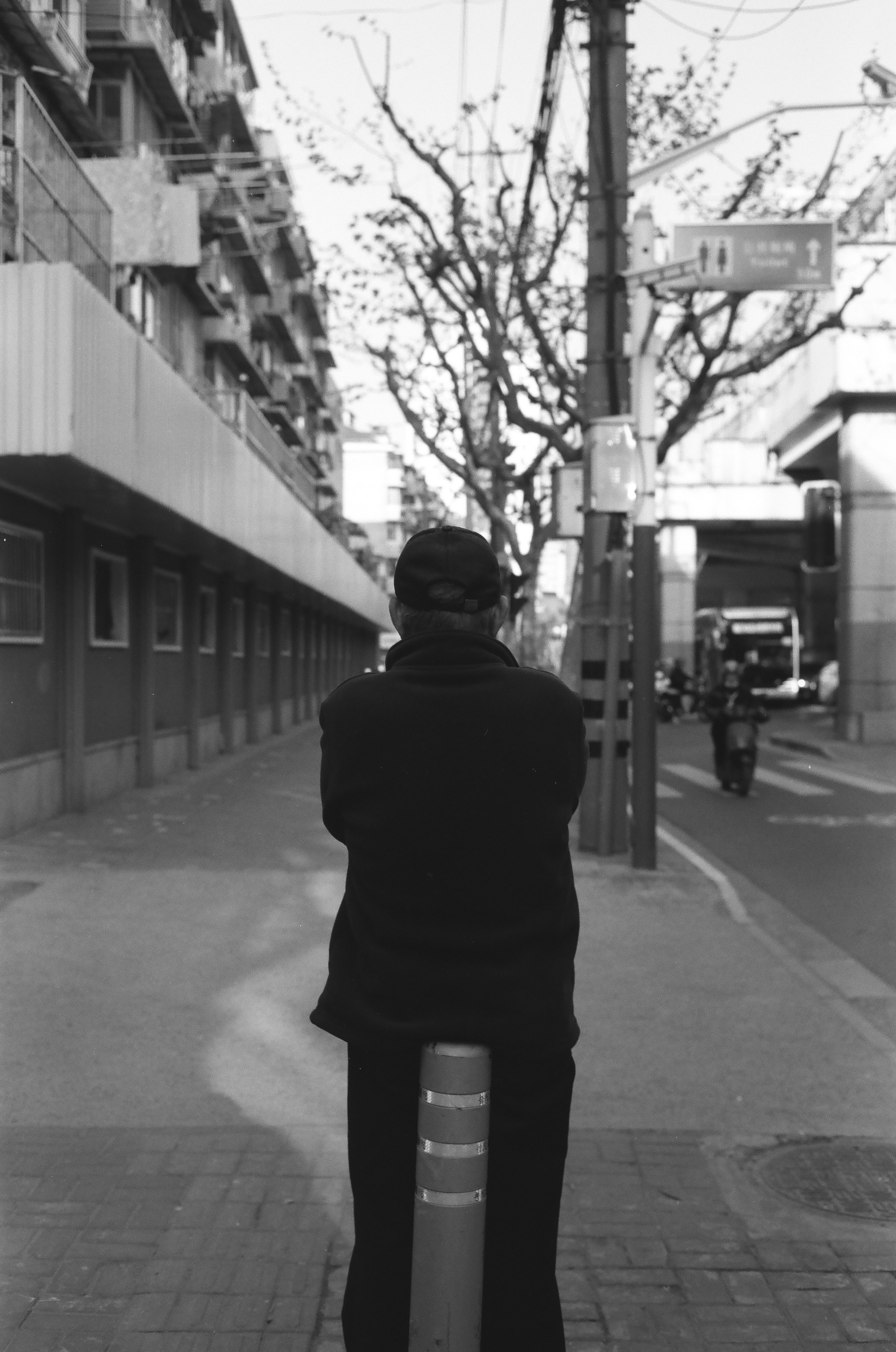 Man leans against a post on a city street. photo – Free China Image on ...