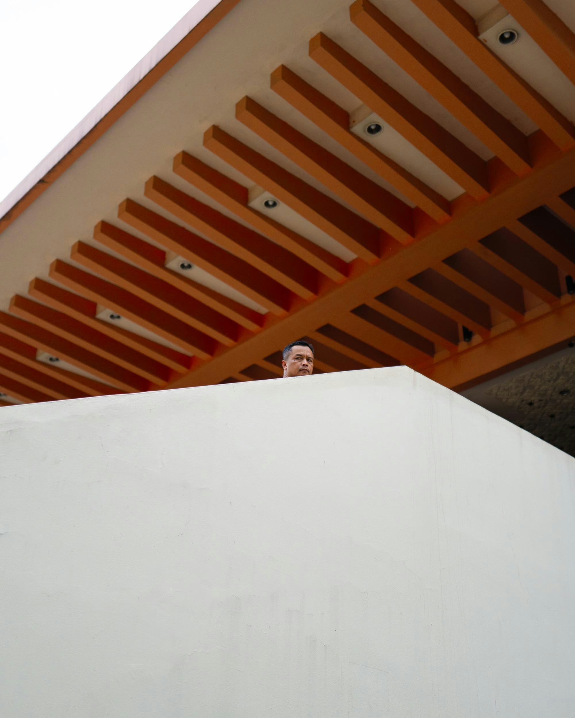 Person peeks over a white wall, under wooden beams. photo – Free Man ...