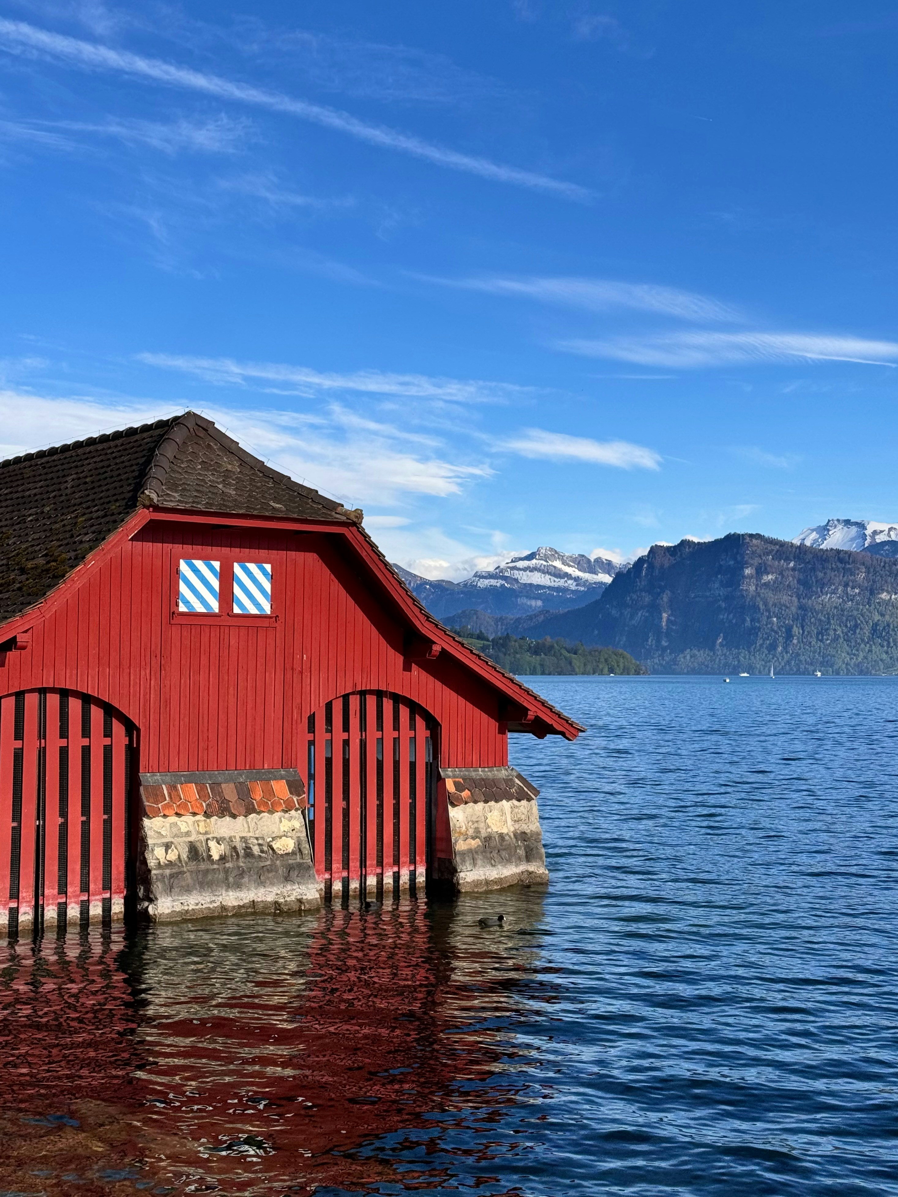 Crimson Boathouse at Lake Edge Under Alpine Sky