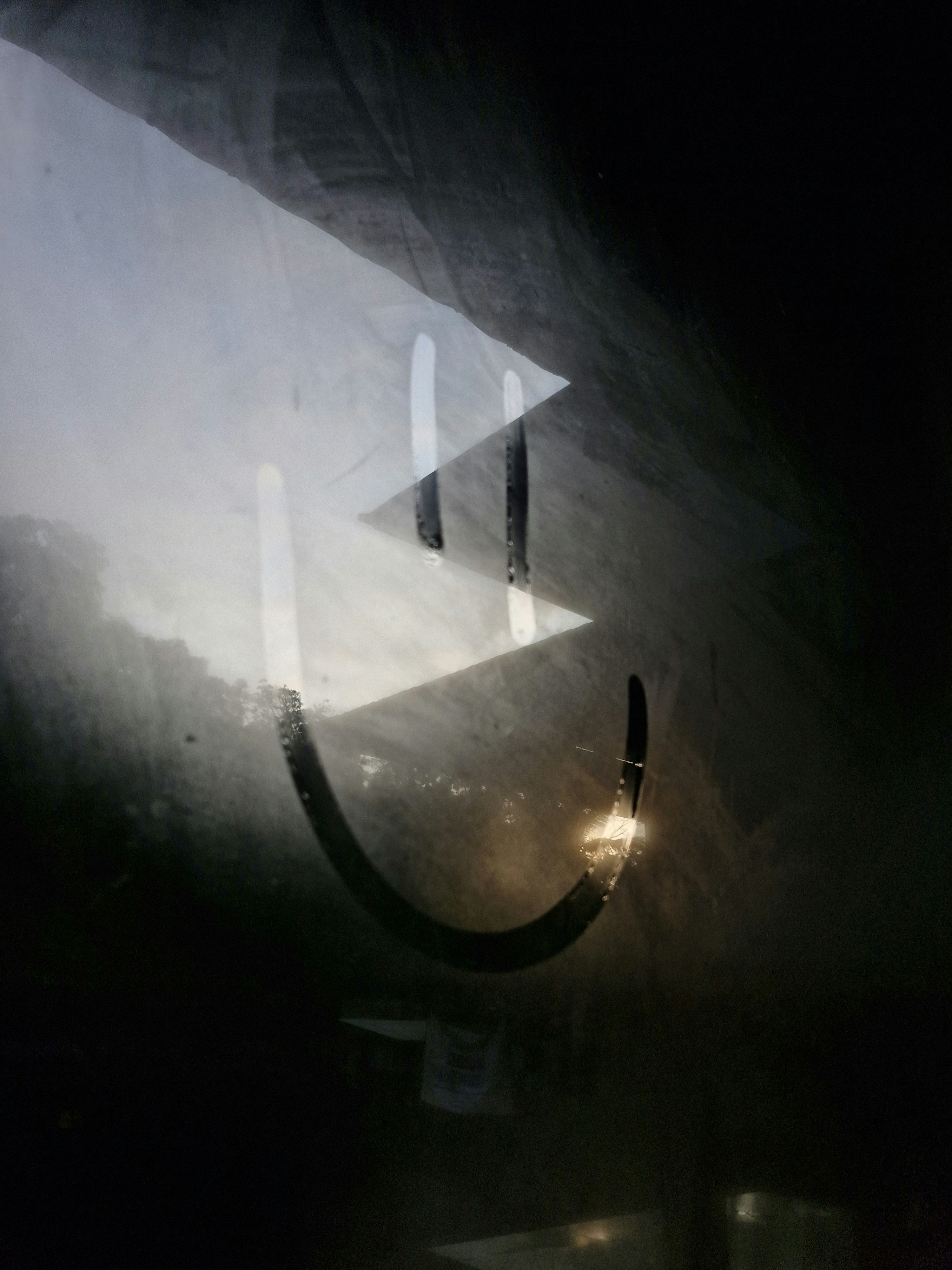 A cheerful smiley face drawn on a fogged glass window, reflecting soft light from an outdoor source.