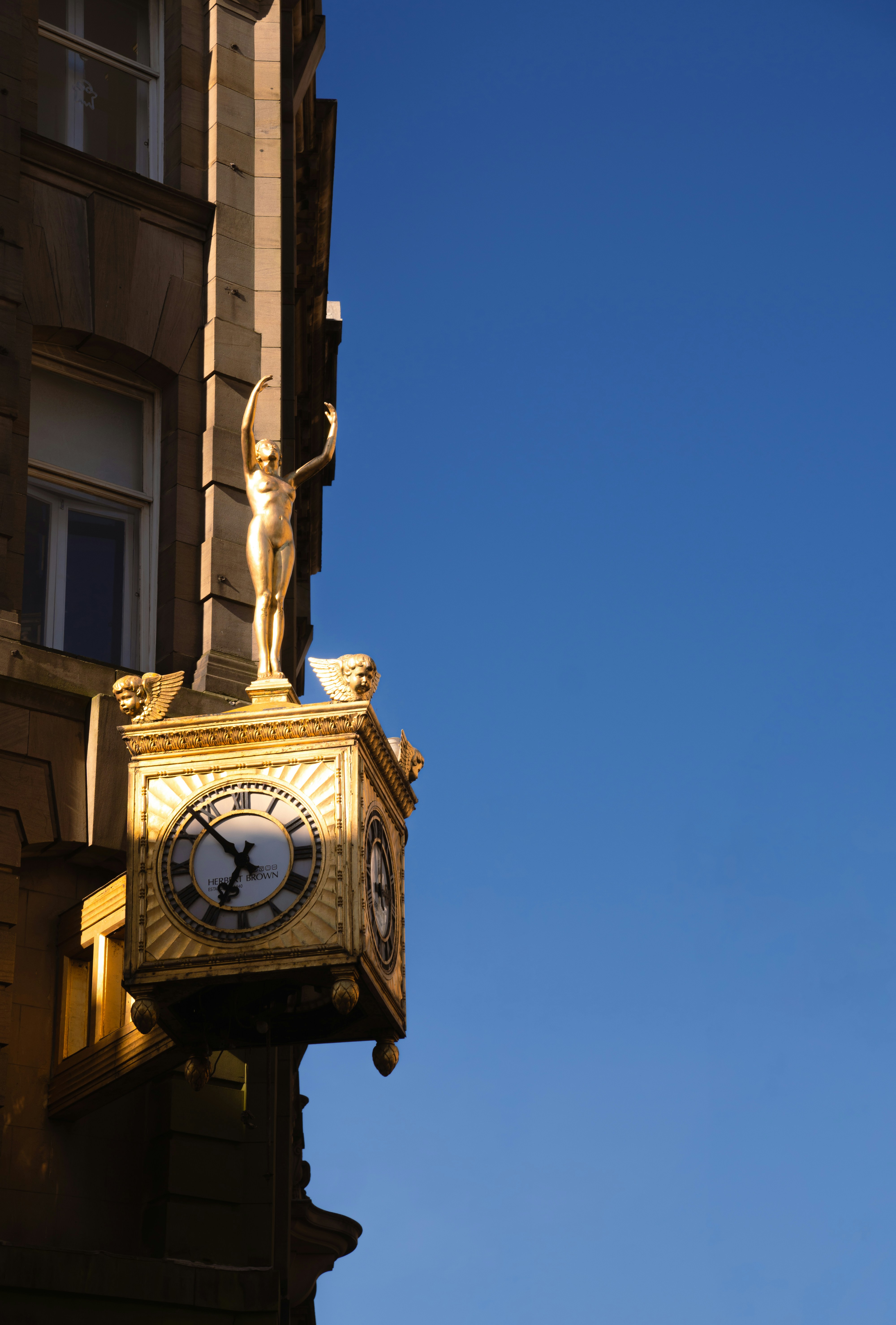 Gilded Clock on a Corner Tower Against a Crisp Blue Sky