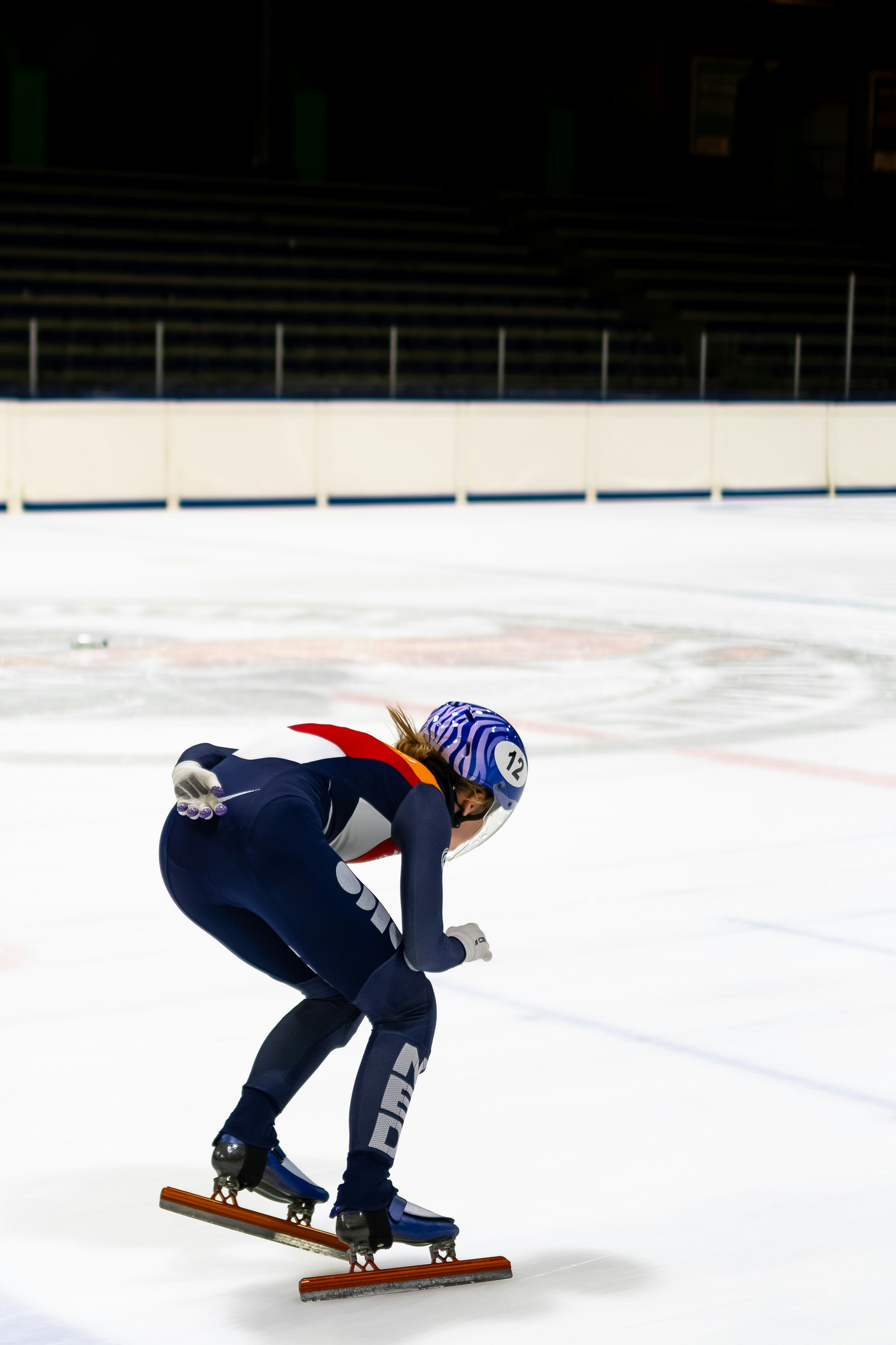 Speed skater in dynamic posture racing across an ice rink, showcasing athleticism and focus.