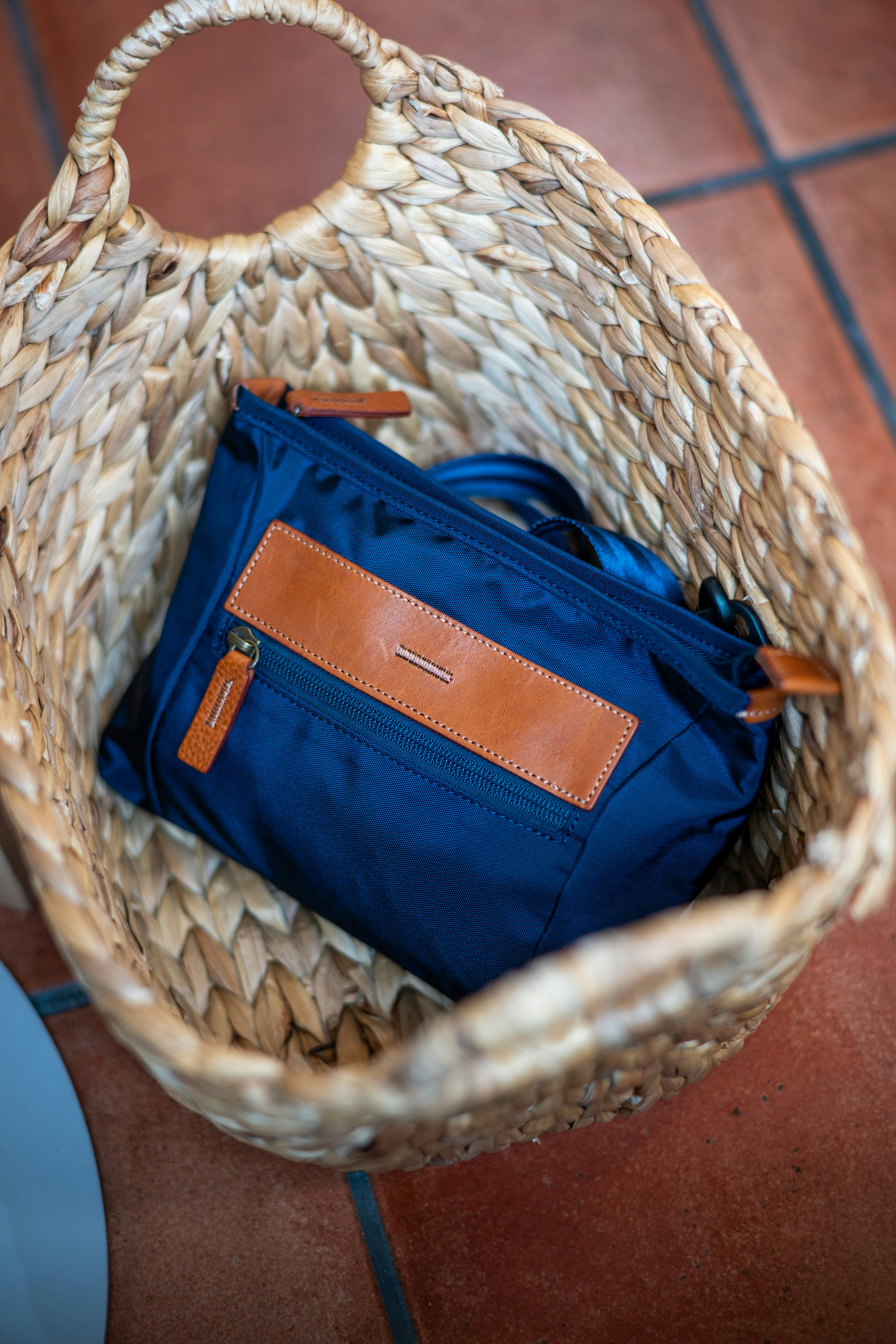 Blue pouch tucked in a woven basket: a sunny study in texture and color