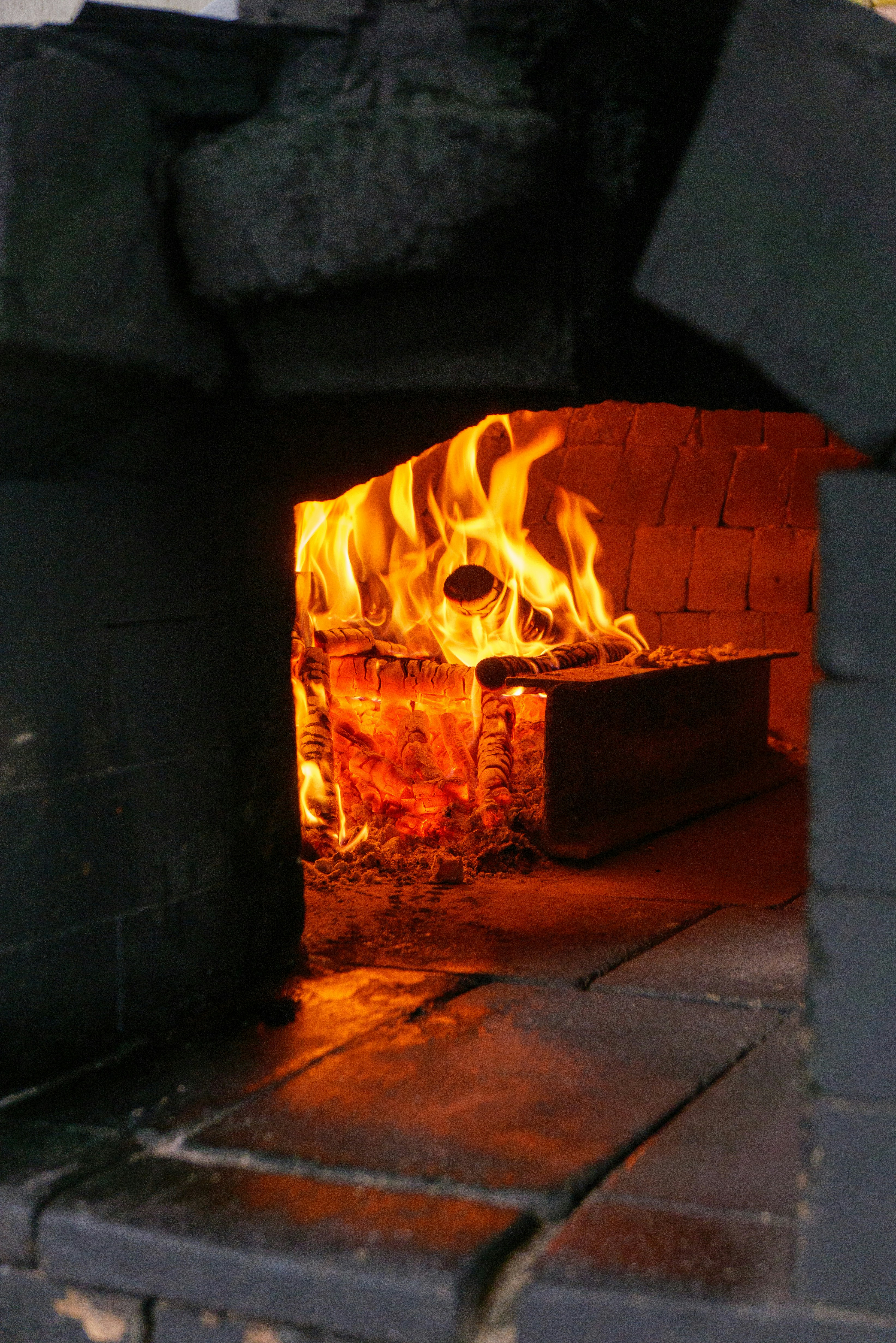 Fire rages inside a brick oven.
