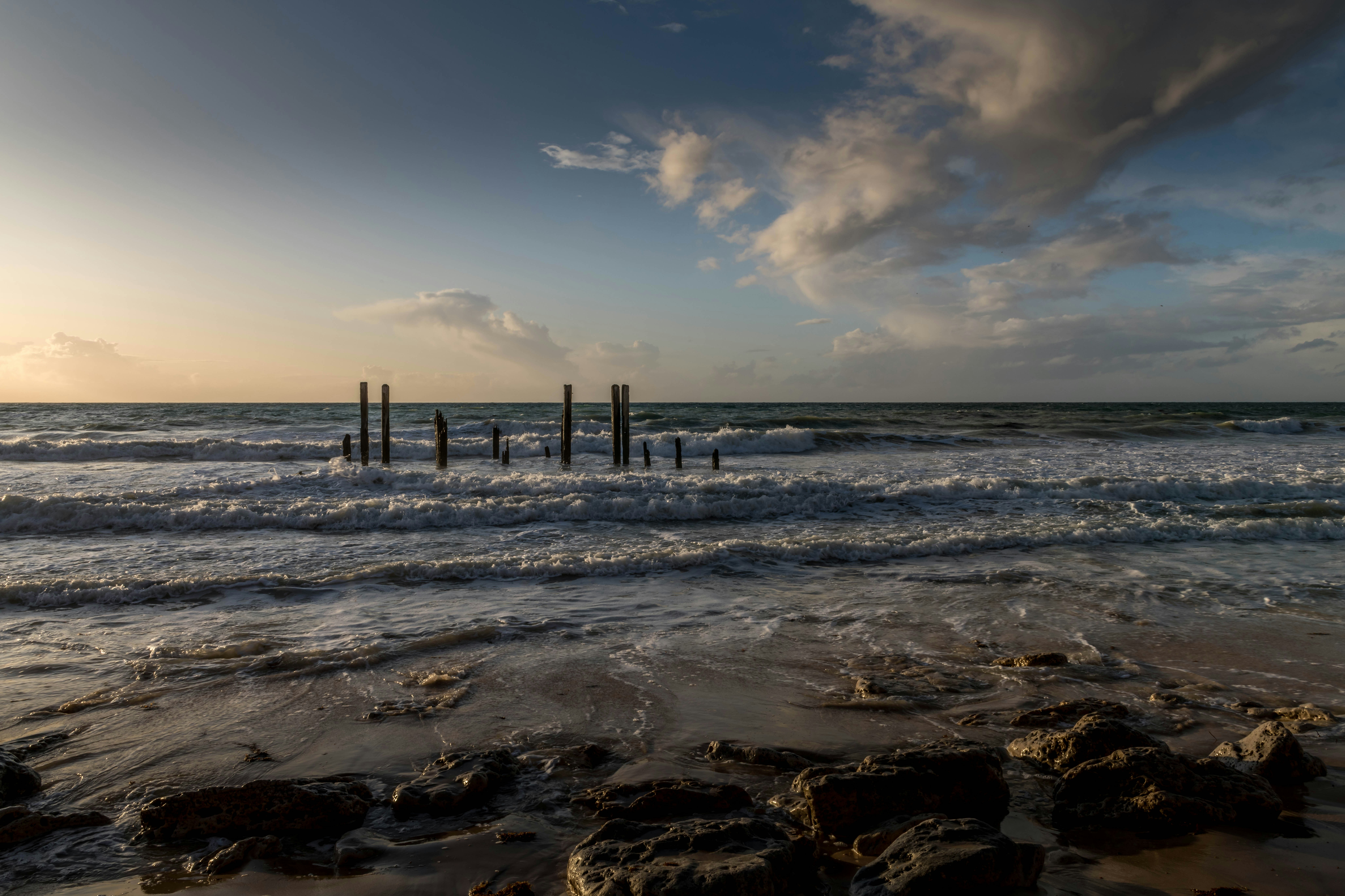 Waves crash on the beach near old pier posts. photo – Free Sea Image on Unsplash