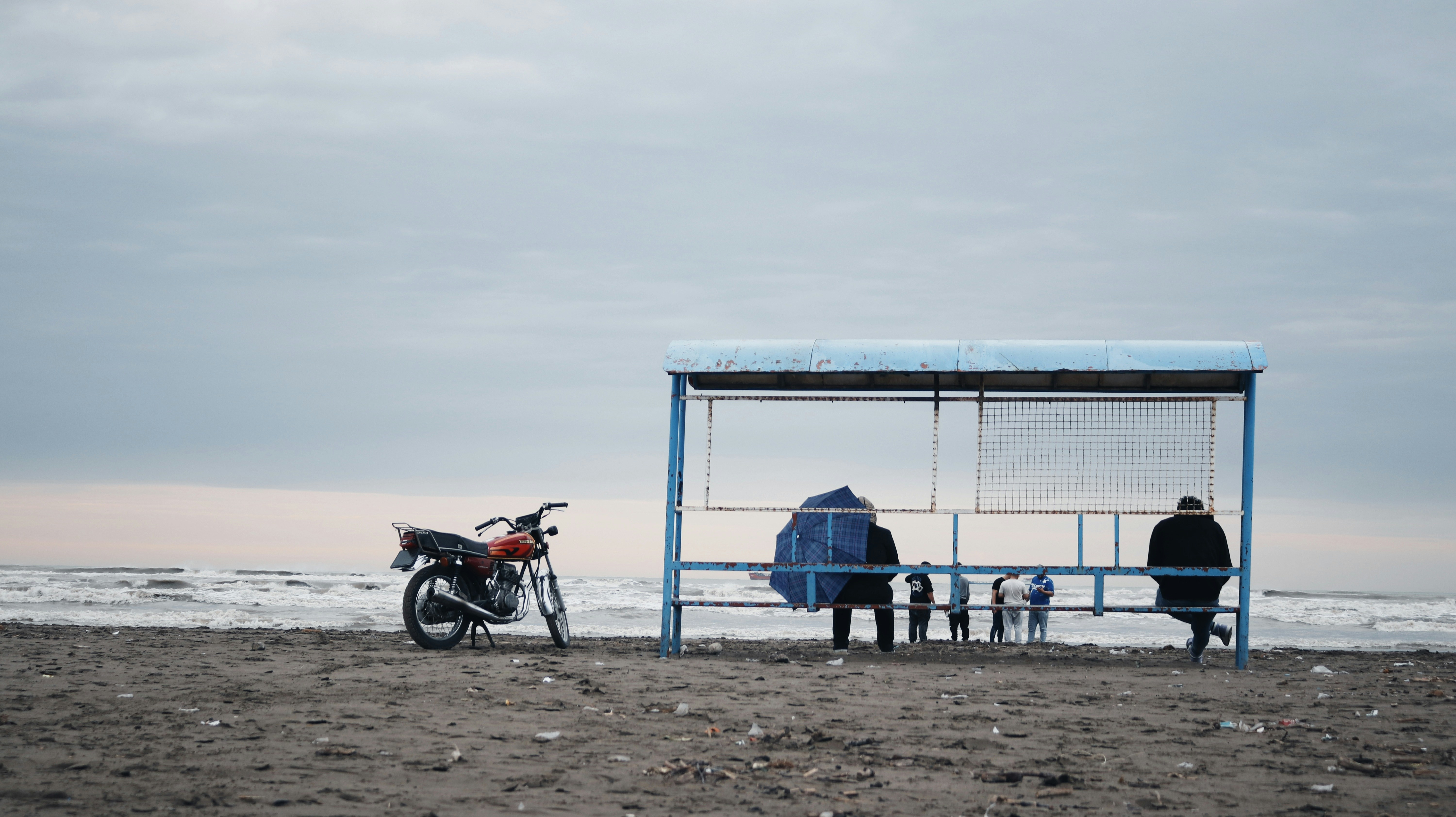People in beach and on bench watching sea