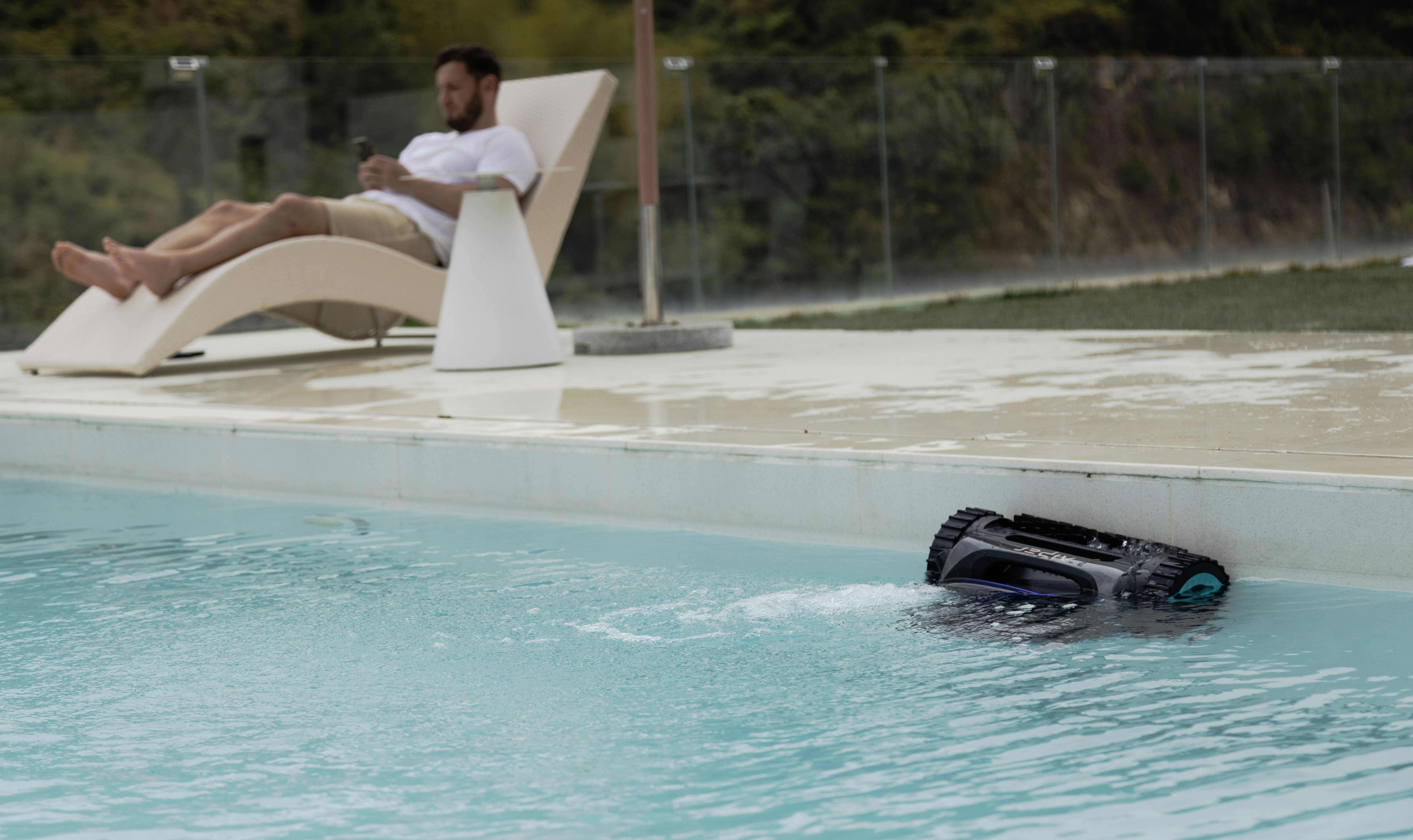 Sunlounger Quiet: A Man Reads as an RC Boat Slices the Pool