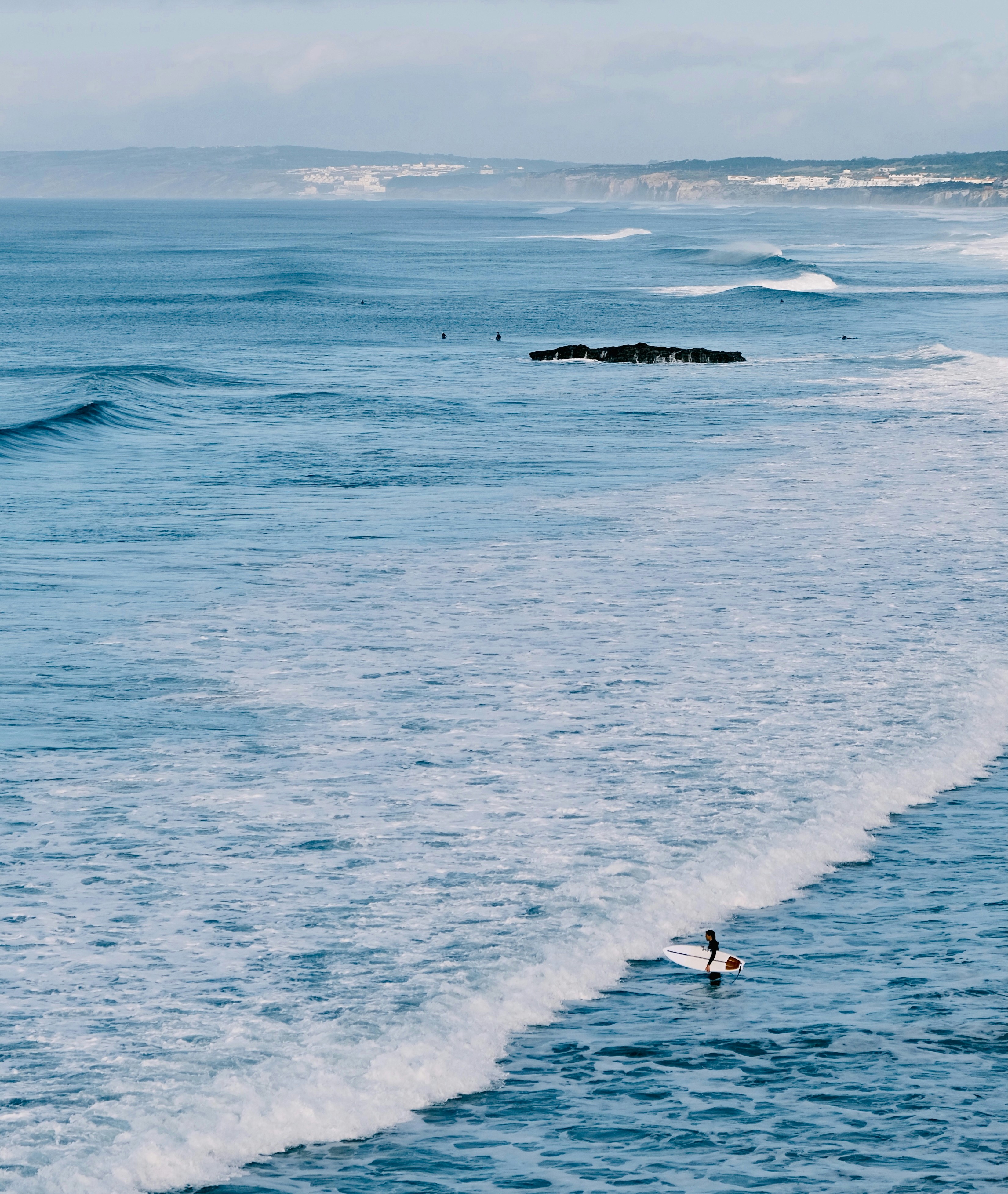 A Surfer stands waiting for the right moment to paddle into the sea, in Peniche, Baleal, Portugal.