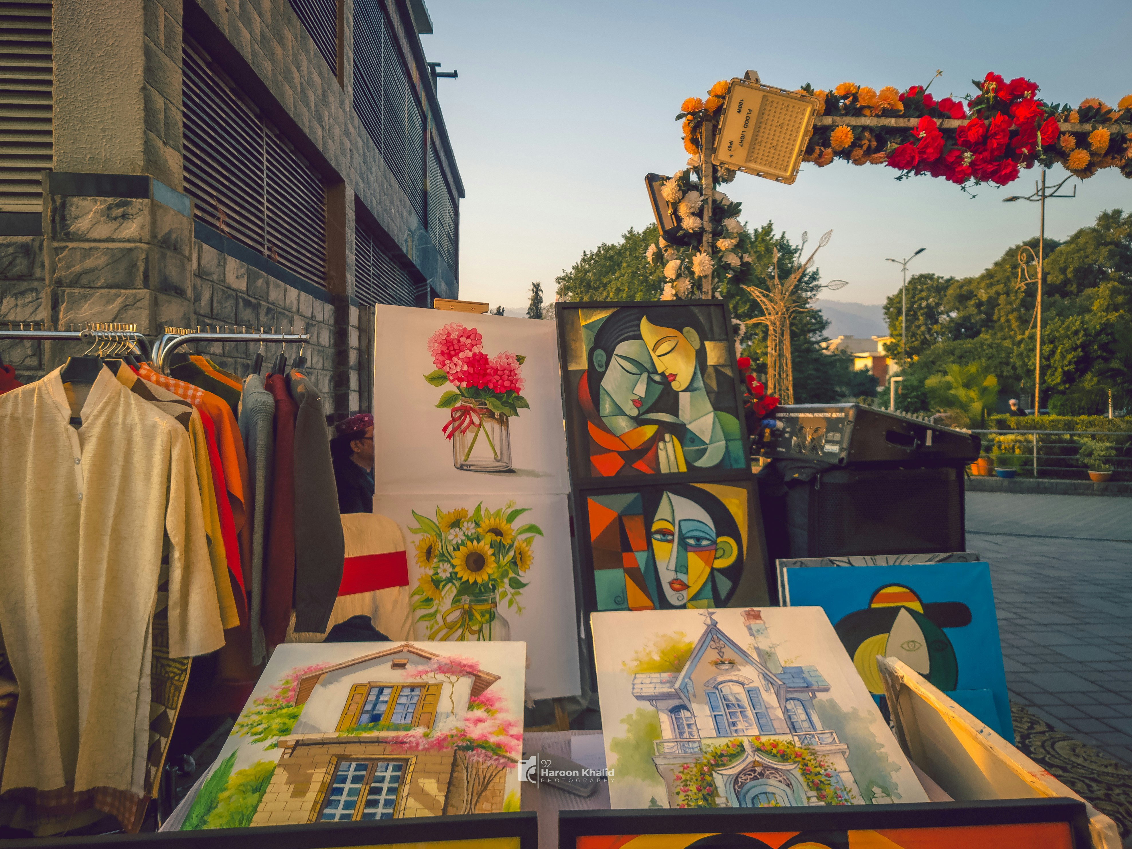 A surreal, abstract artwork capturing the essence of a face through fragmented, cubist-style shapes reminiscent of Picasso's influence. The use of bold, layered textures and geometric color blocks creates a striking visual that feels both artistic and emotional, evoking depth and curiosity. | Art, clothes, and decorations at an outdoor market.