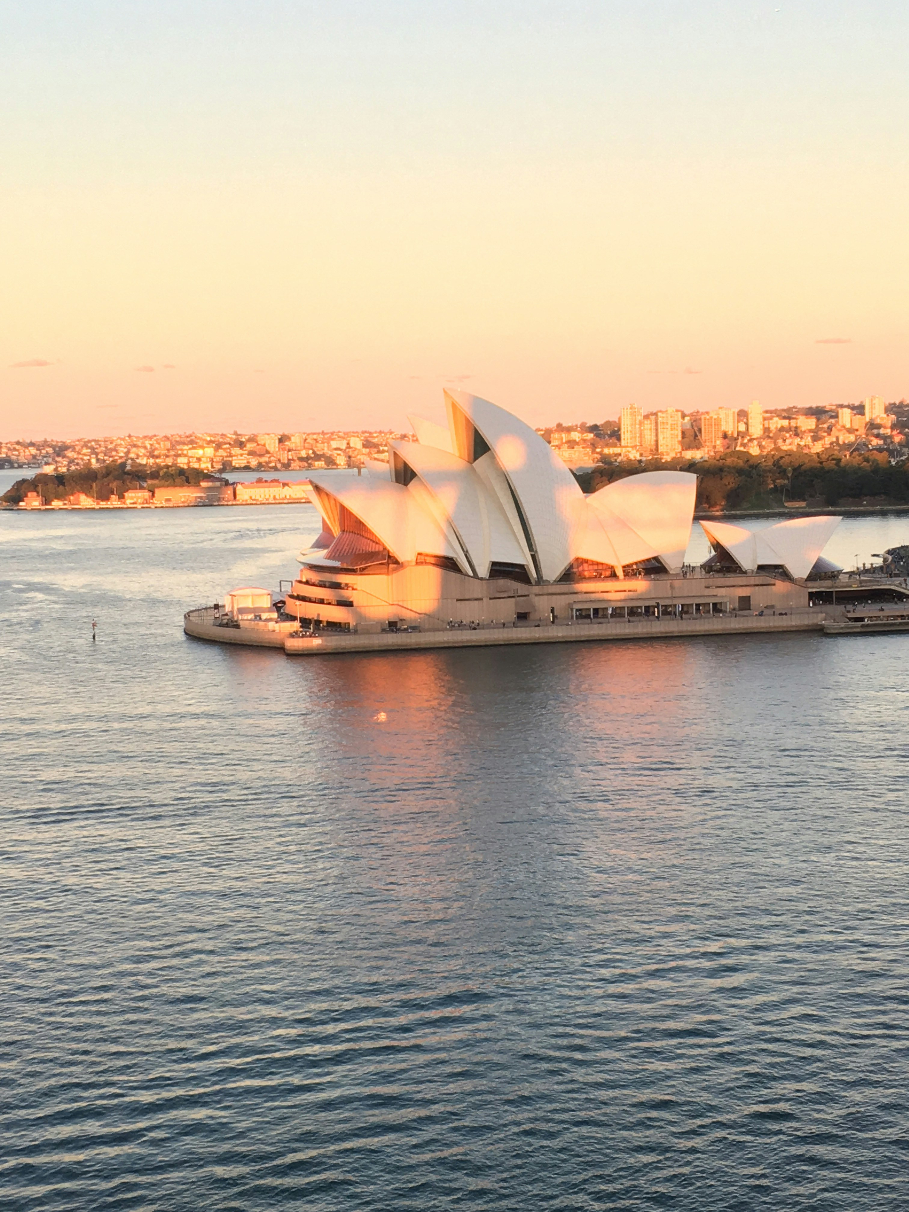 A stunning view of the Sydney Opera House bathed in the warm golden light of sunset, reflecting beautifully on the waters of Sydney Harbour. This iconic piece of modern architecture stands as a testament to Australia’s cultural heritage, offering a breathtaking perspective of both nature and urban design. The Sydney Opera House is a must-see landmark, drawing visitors from all around the world to experience its architectural beauty and vibrant cultural scene.