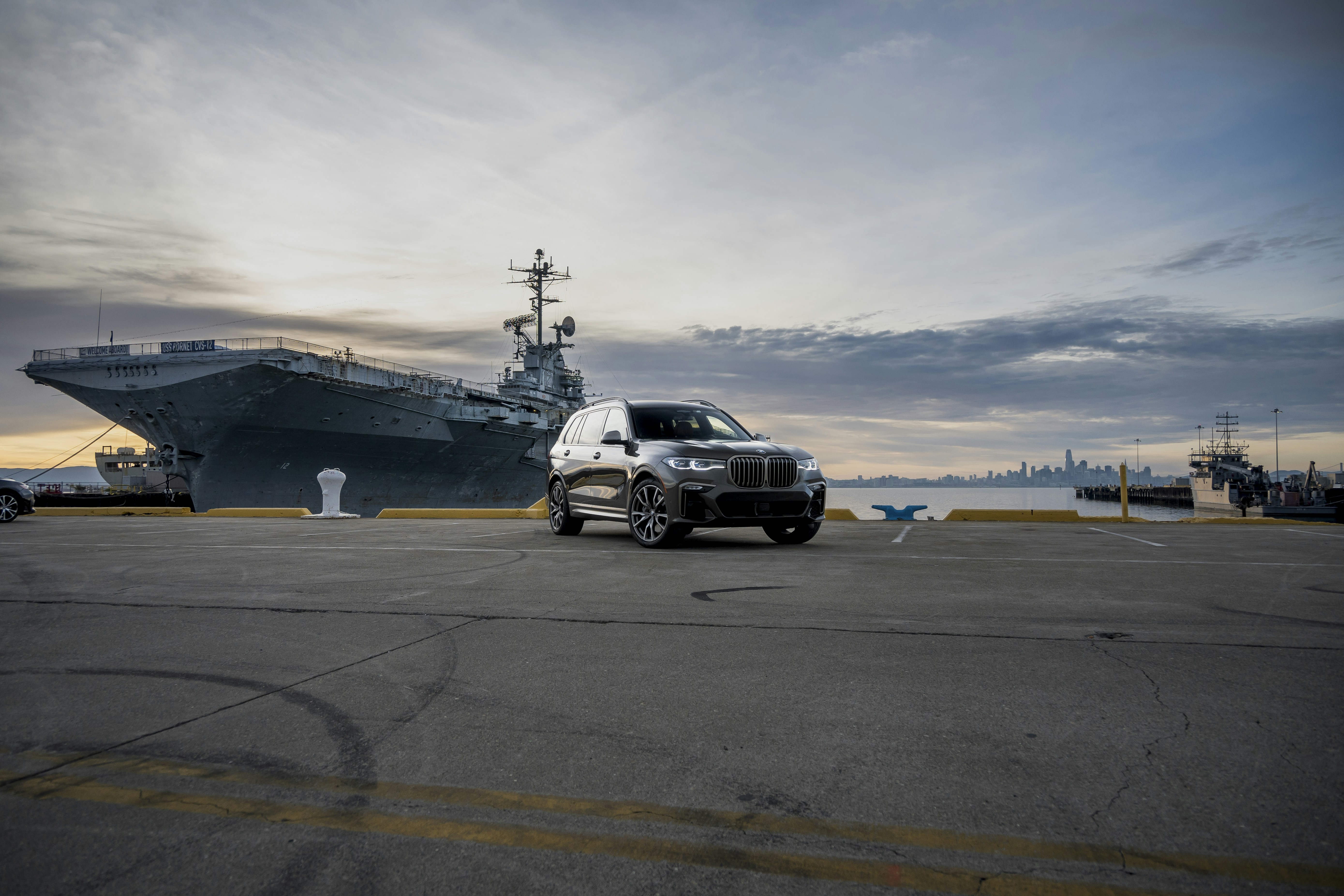 Pierside Contrast: SUV Under a Carrier at Twilight