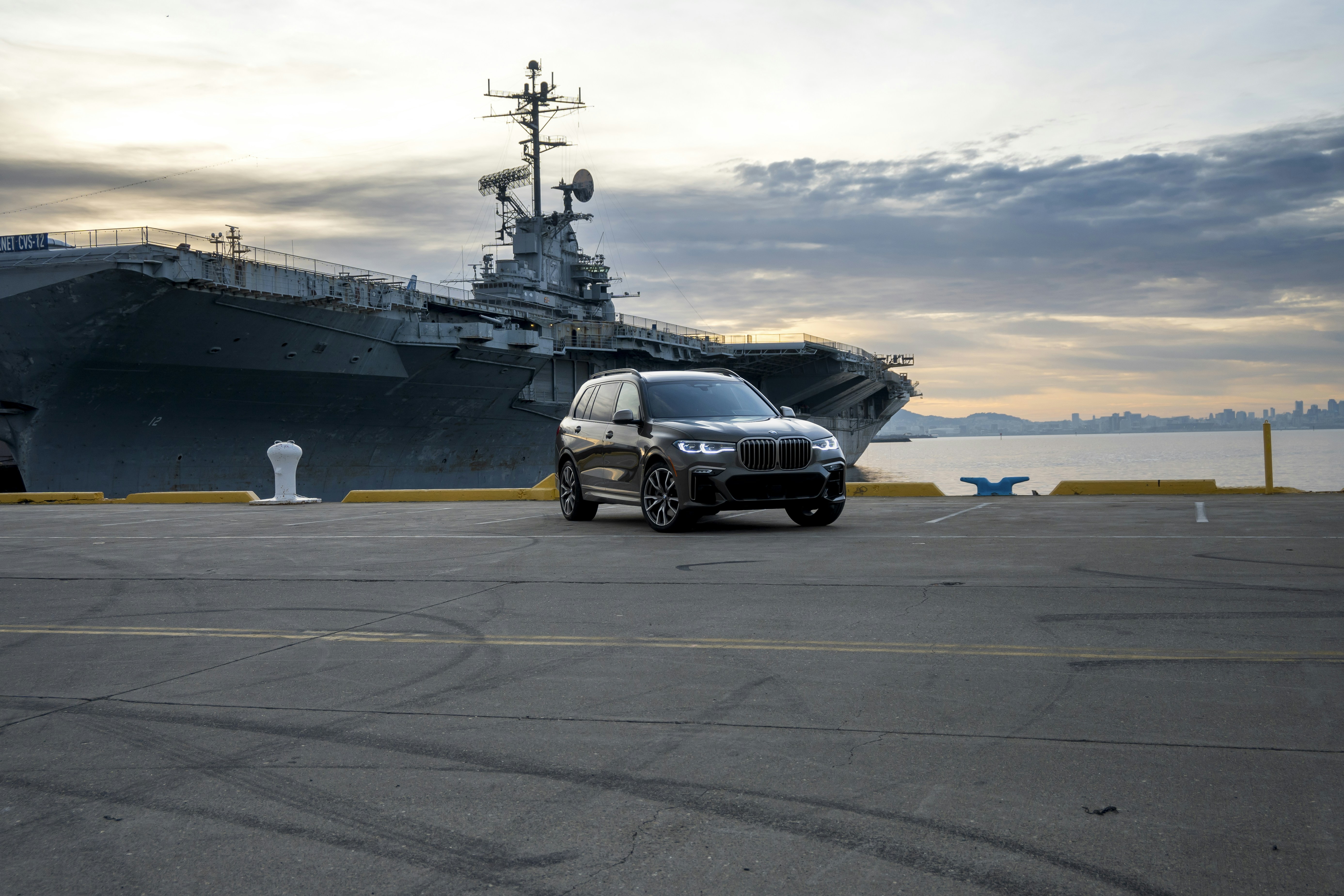 Harbor Standstill: SUV Framed by a Carrier at Sunset