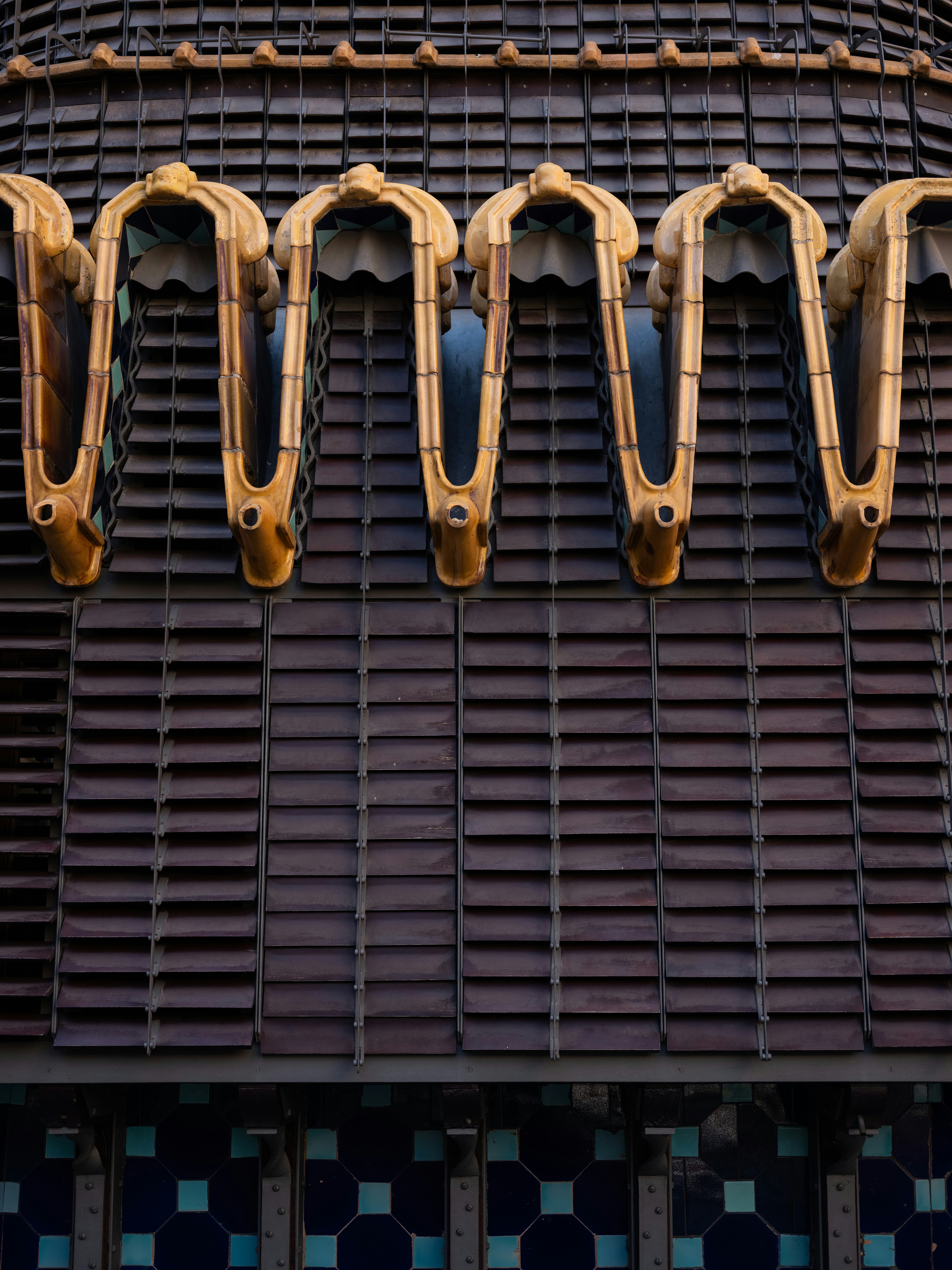 Bronze Arches on a Dark Lattice: Close-Up of Repeating Hardware