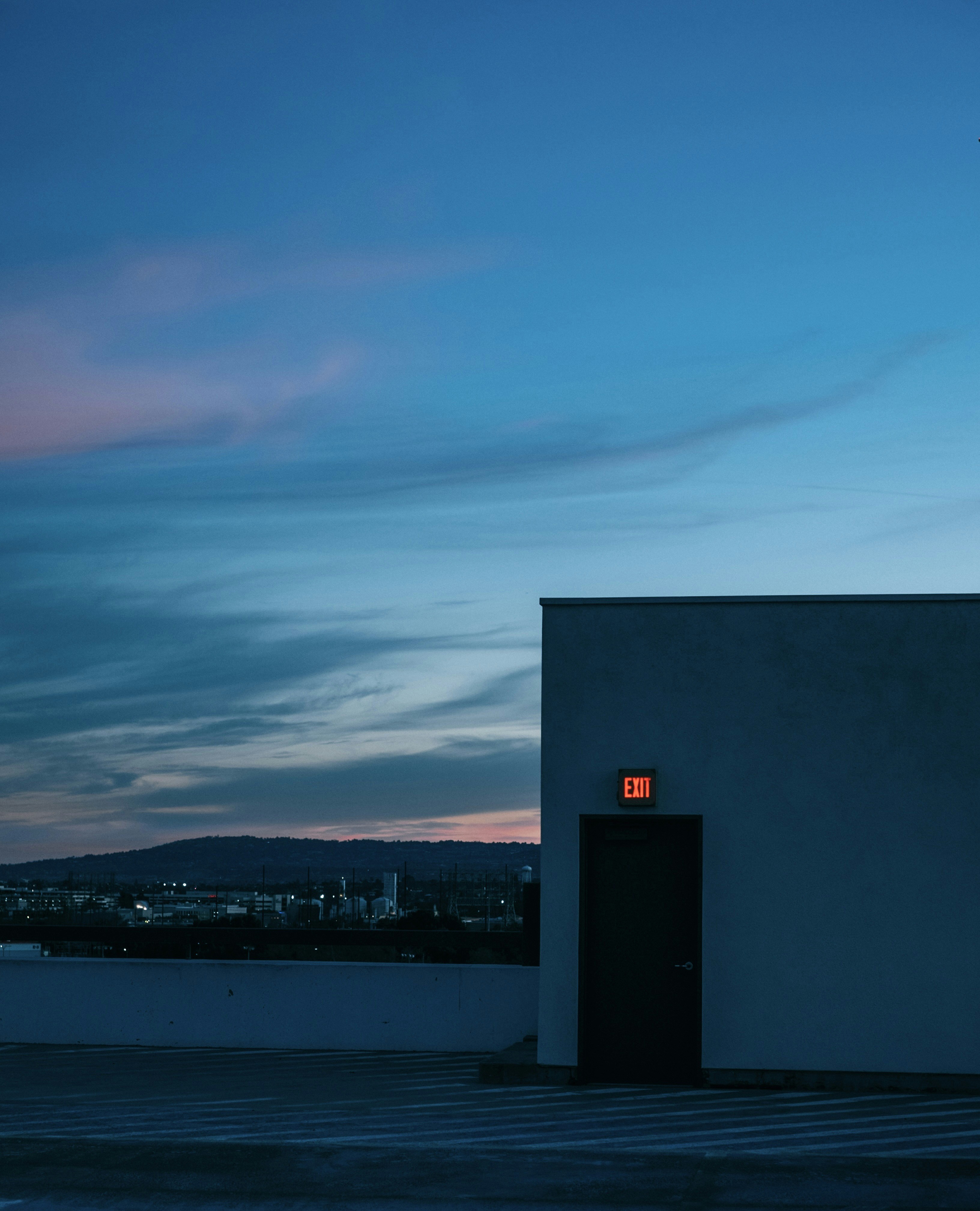 Blue Hour Rooftop: The Red Exit Sign Guarding the Distant City