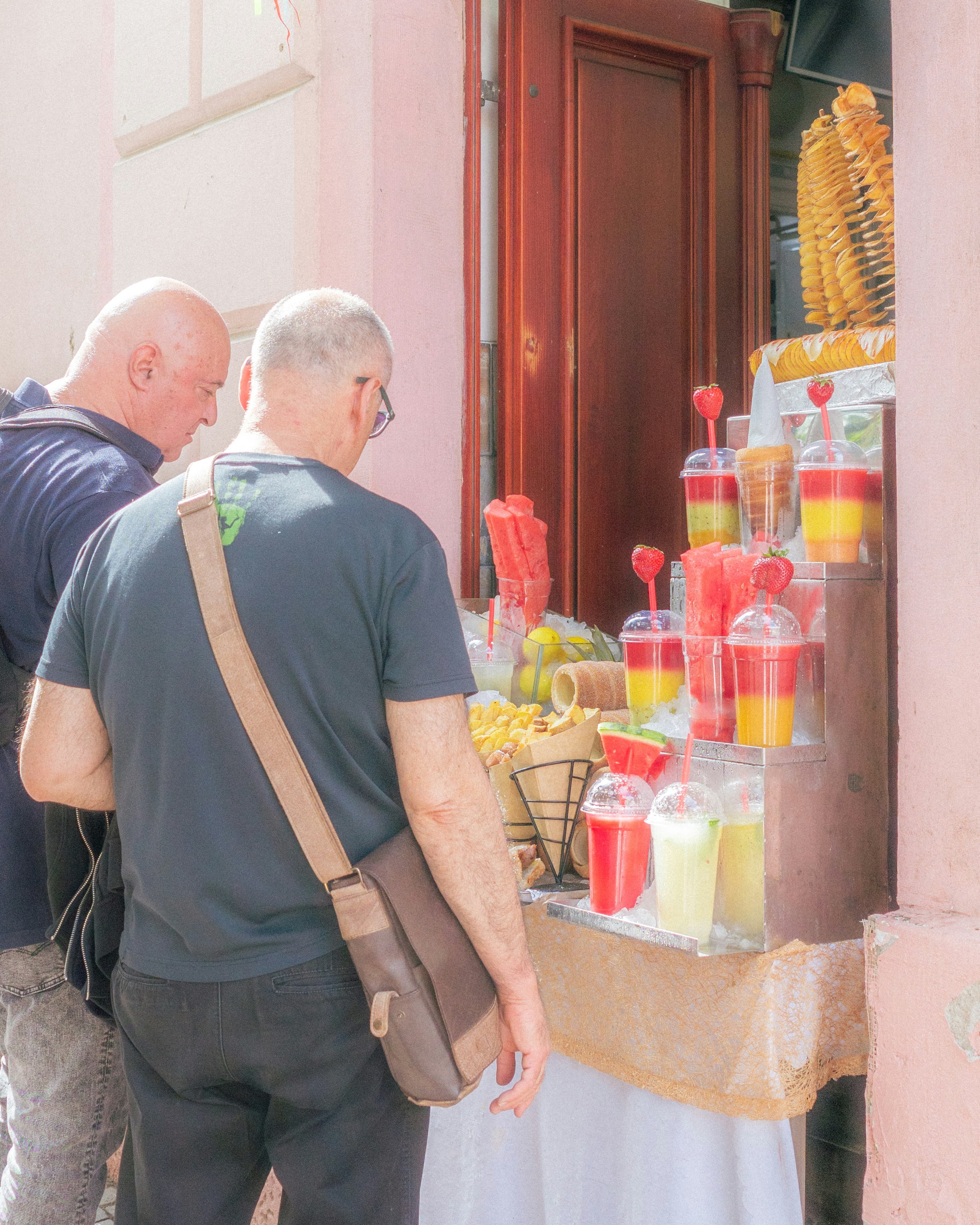 Candy-Colored Drinks at a Sunlit Street Stall, Framed by Shoppers