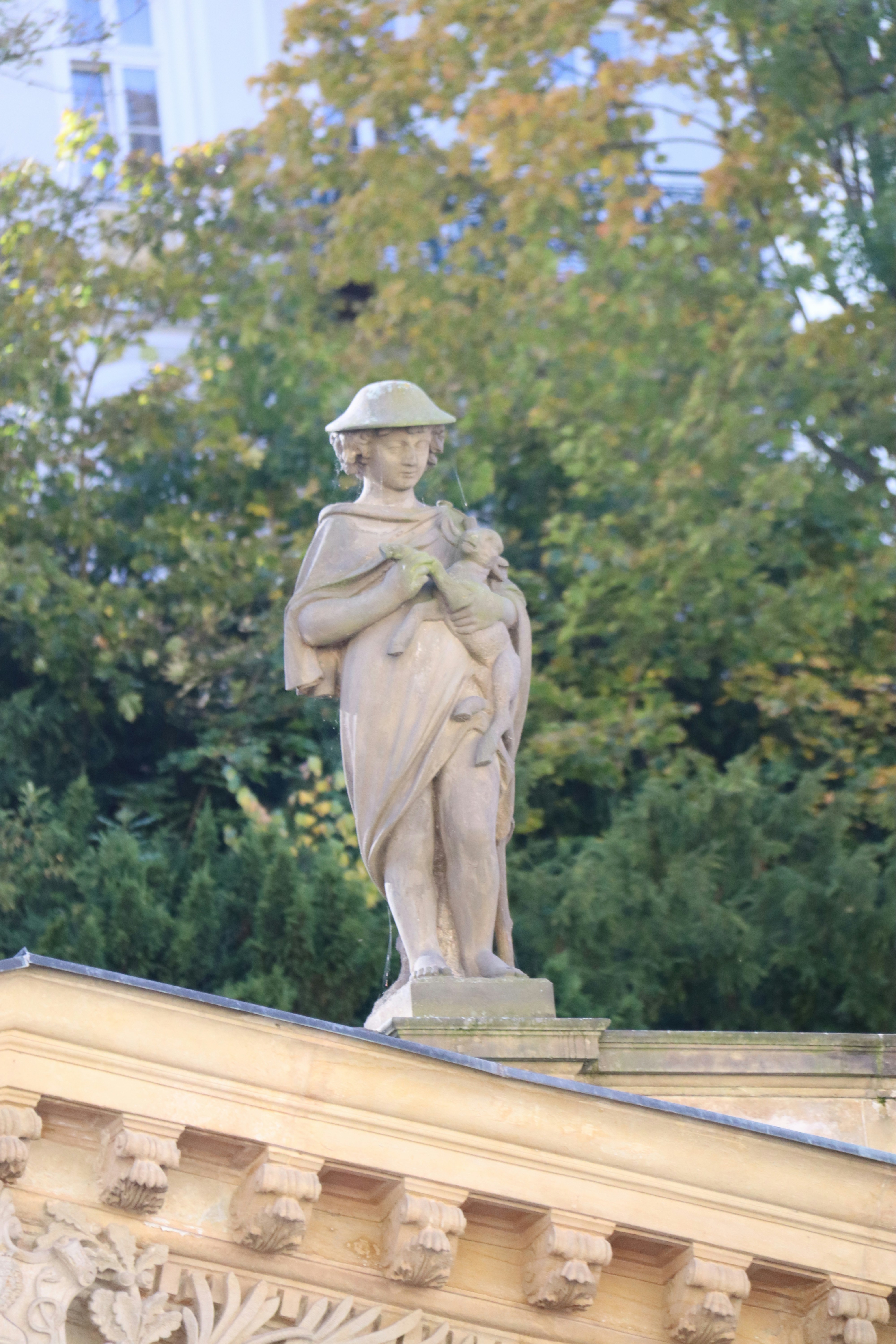 Stone Sentinel on a Balustrade Amid Autumn Foliage