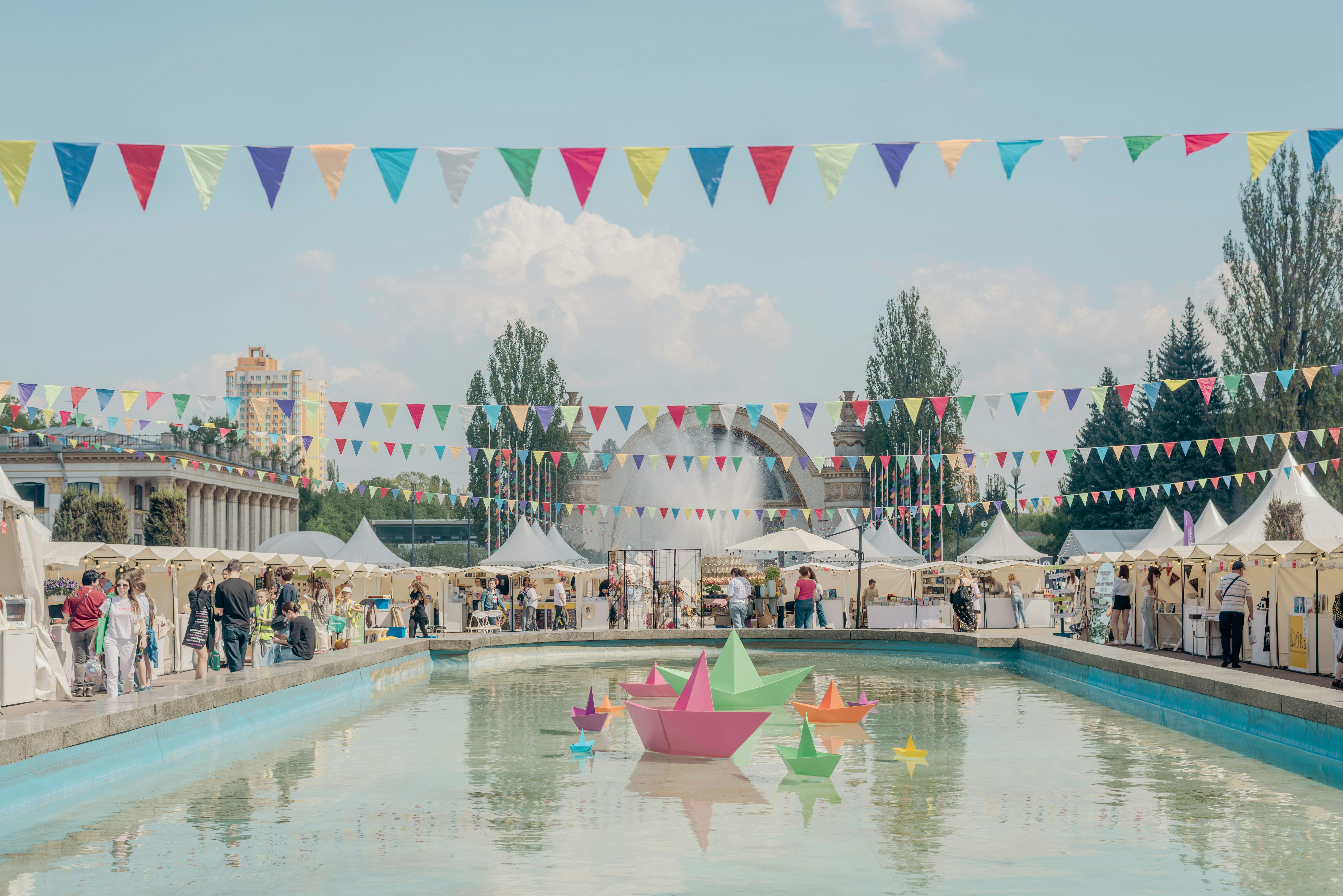 Floating Origami Under a Canopy of Flags at a Sunlit Festival Pool