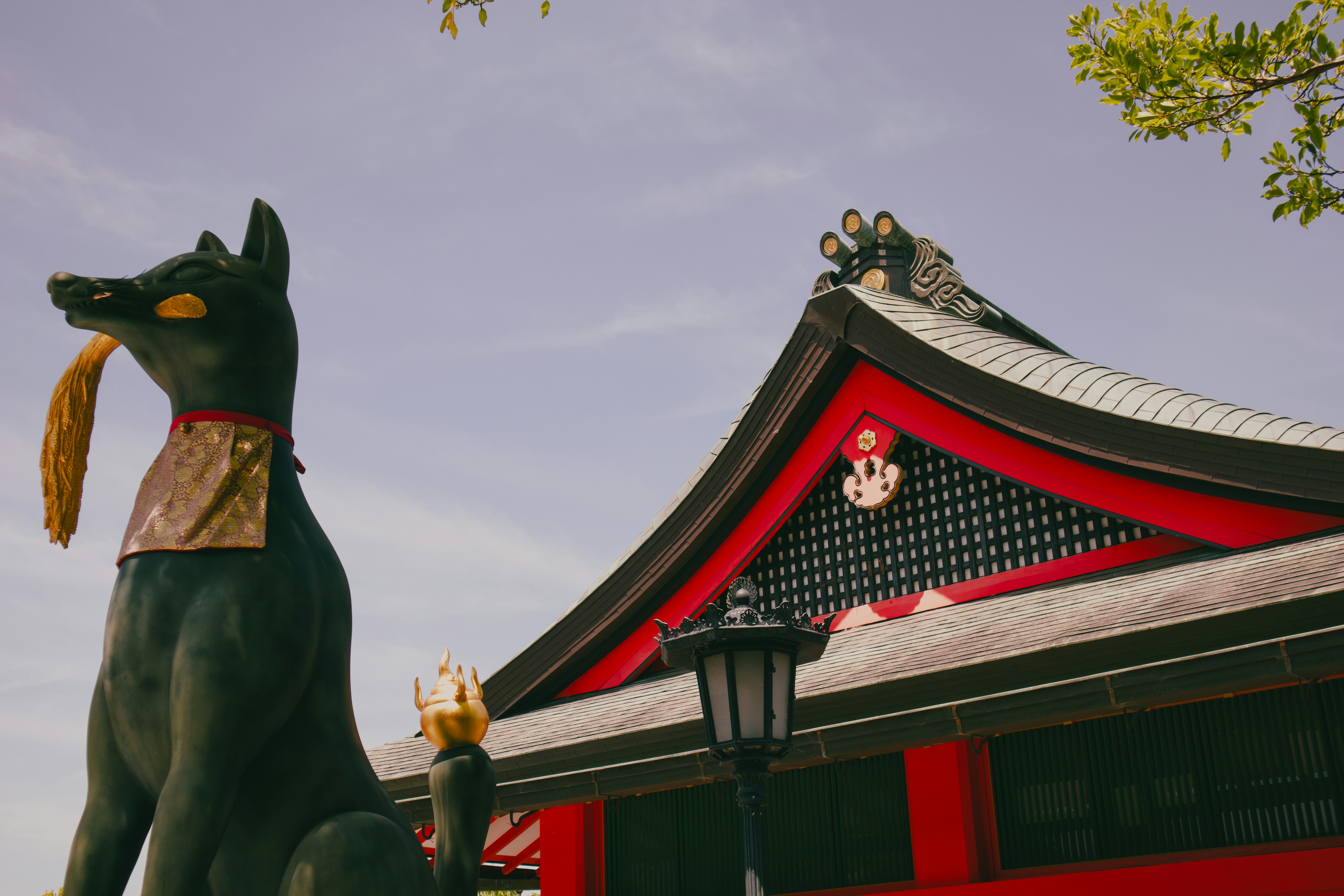 A black fox statue stands near a japanese temple.
