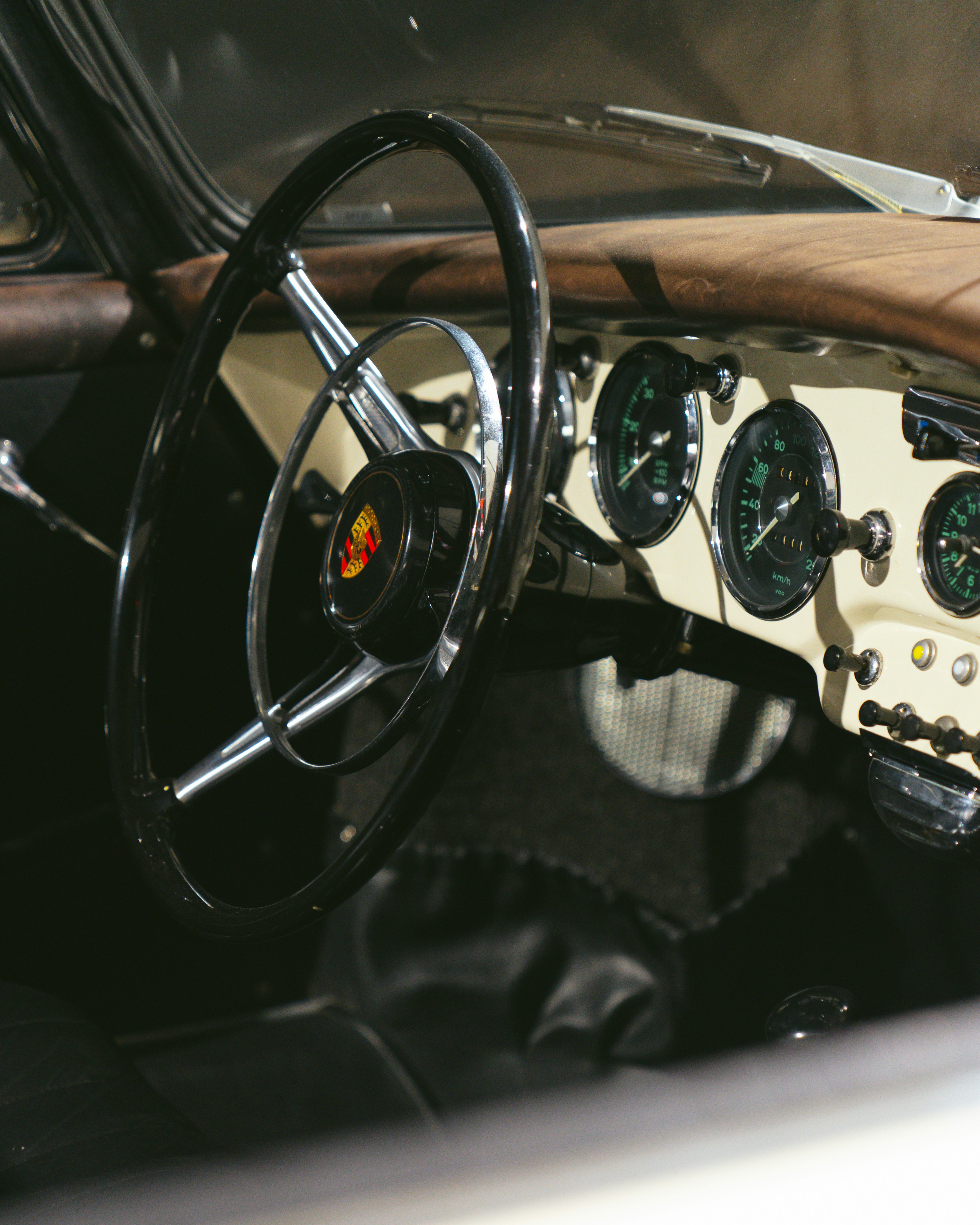 Vintage car dashboard featuring a polished steering wheel and retro gauges, showcasing intricate details of automotive craftsmanship.