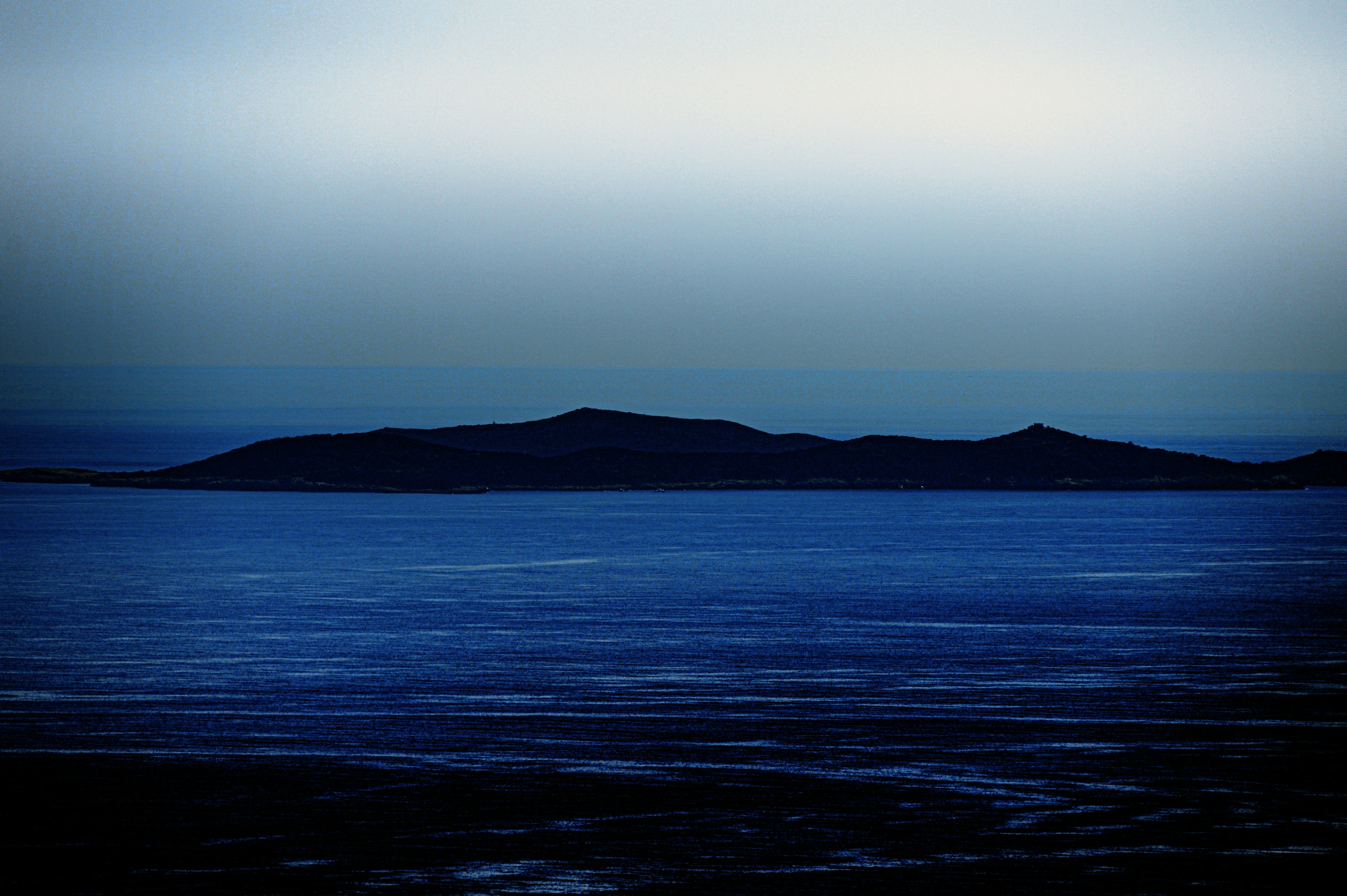 Mountains rise above a dark, blue ocean. photo – Free Wallpaper 4k ...