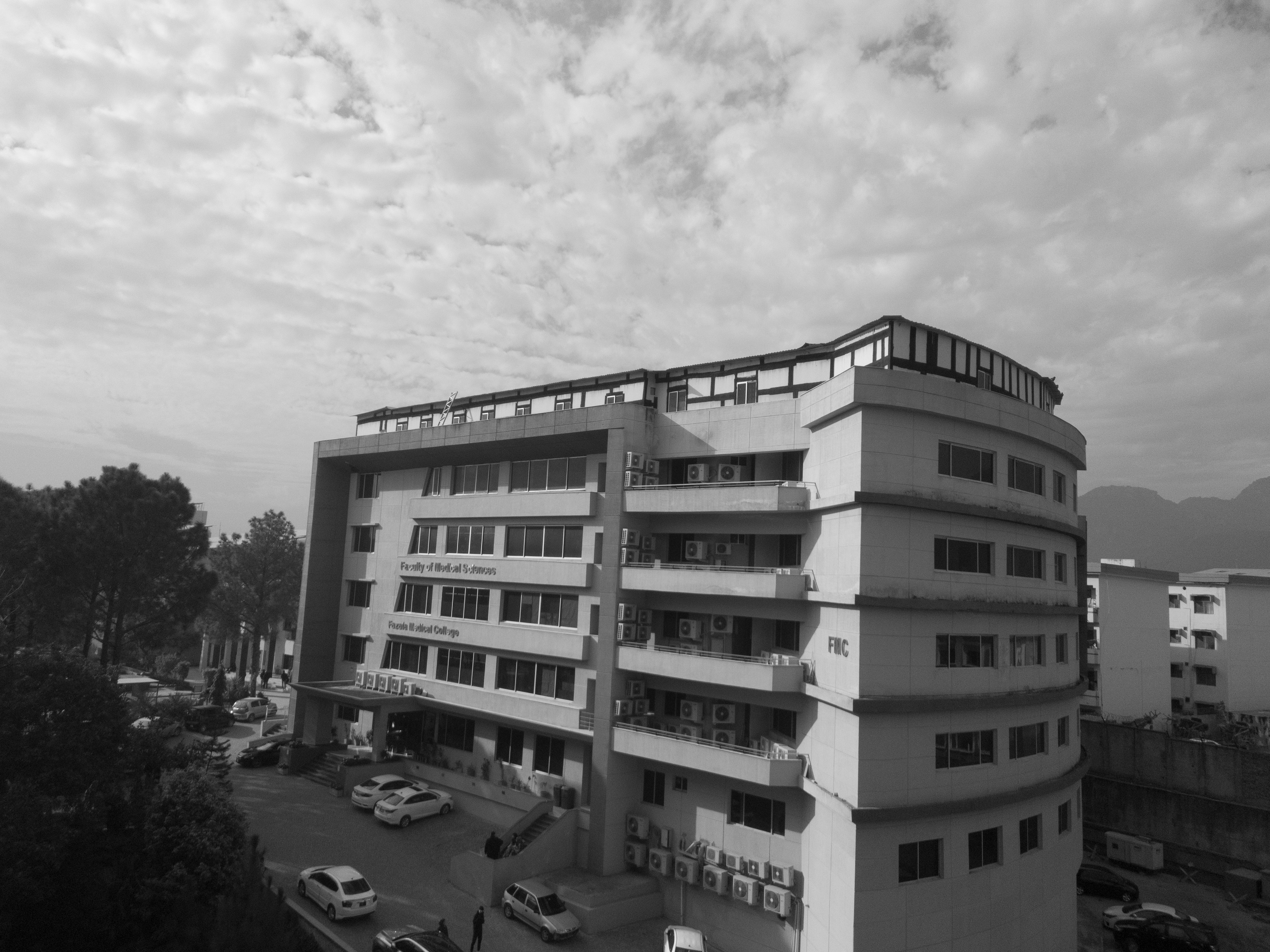 A striking black-and-white landscape photograph of Air University's academic block, showcasing its architectural grandeur in monochrome. The high-contrast tones highlight the building's structure, symmetry, and academic ambiance—ideal for educational themes, institutional branding, or minimalist architecture portfolios.