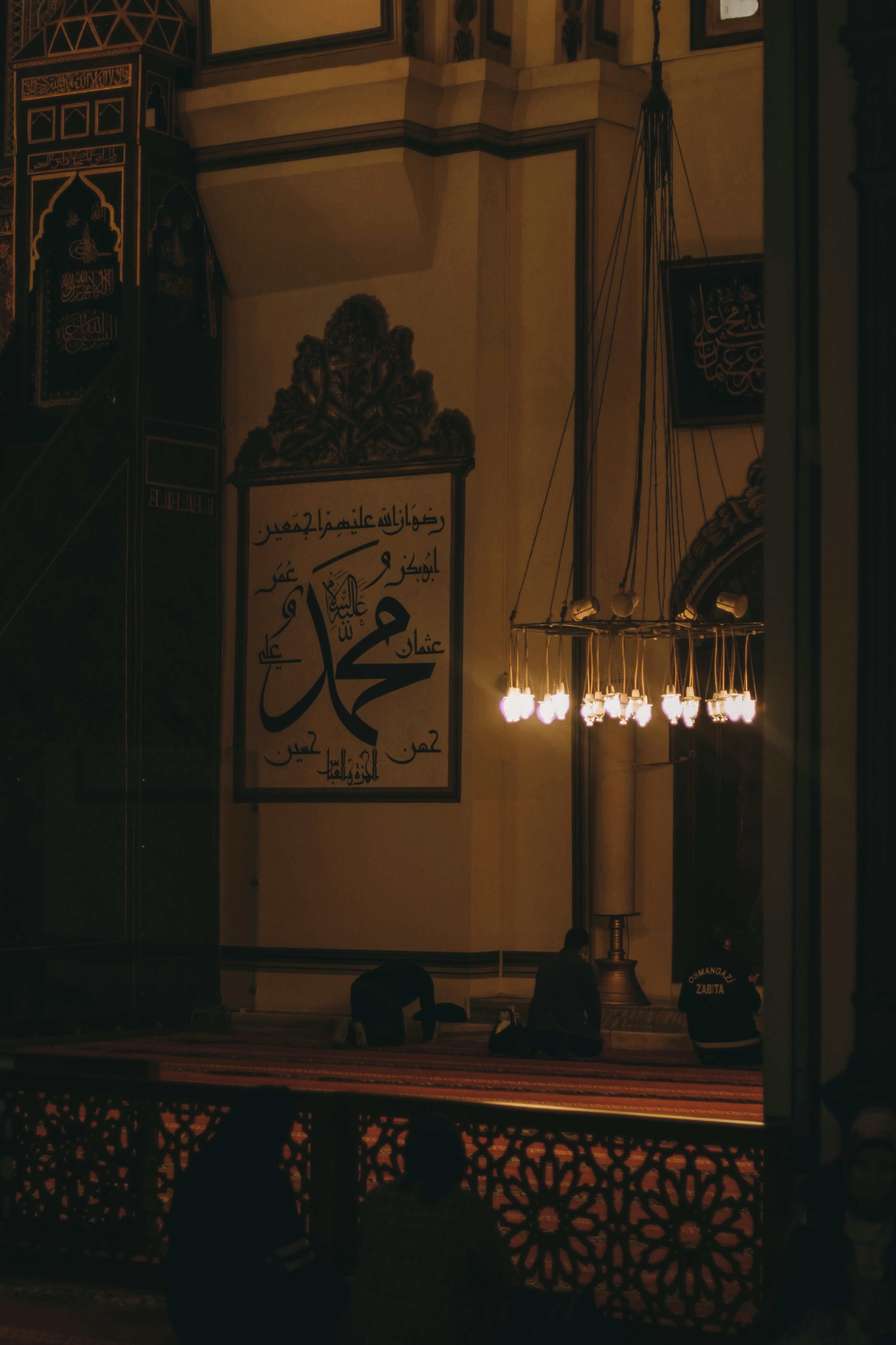 People pray in a beautifully lit mosque.